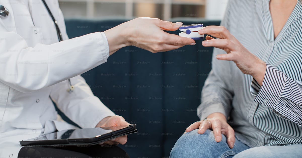 환자의 산소 포화도를 확인하기 위해 가정 방문 중에 손가락 끝 맥박 산소 측정기로 Ptoective 마스크로 노인 환자를