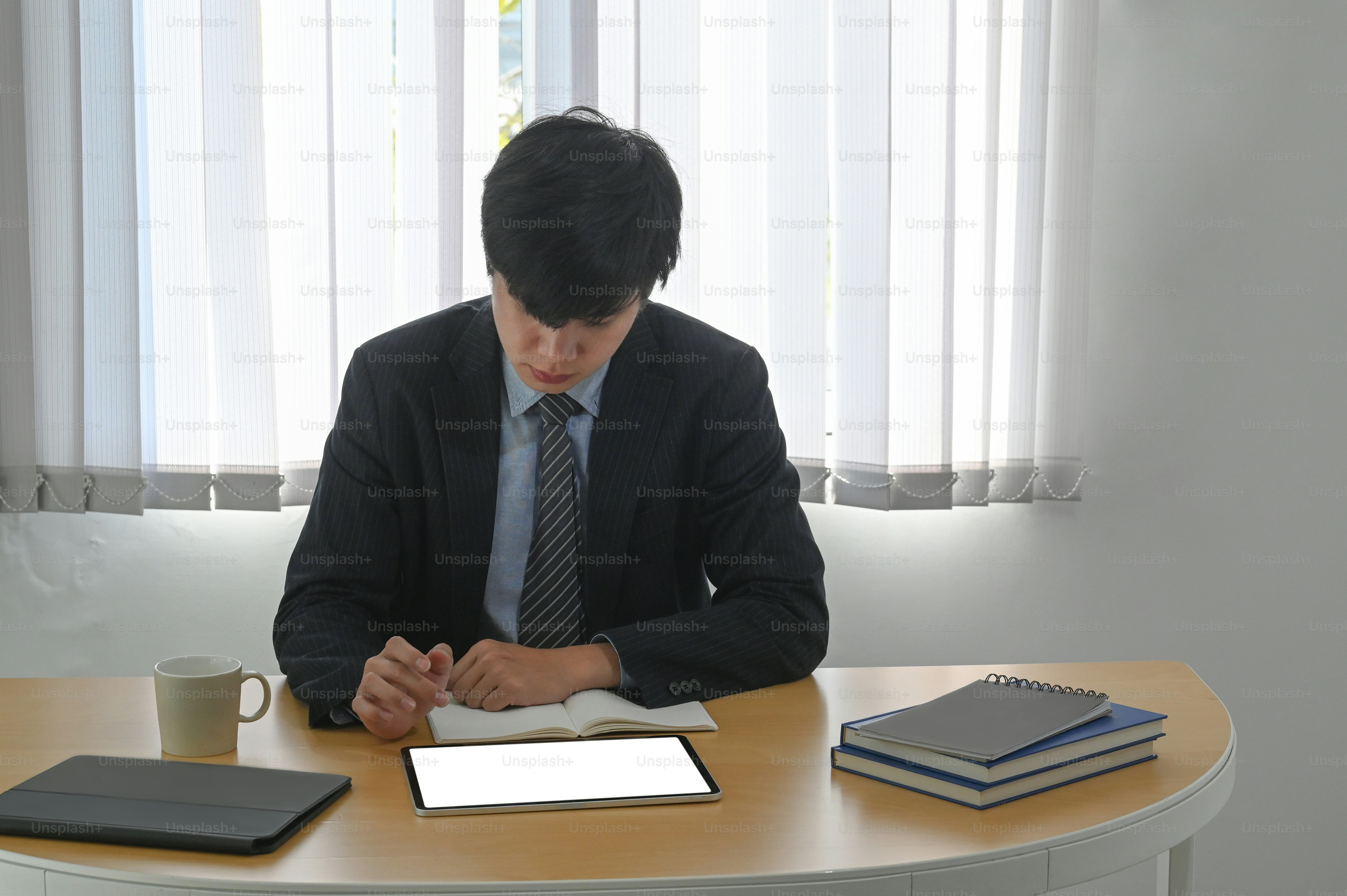 Businessman making note on notebook and working with digital tablet at ...