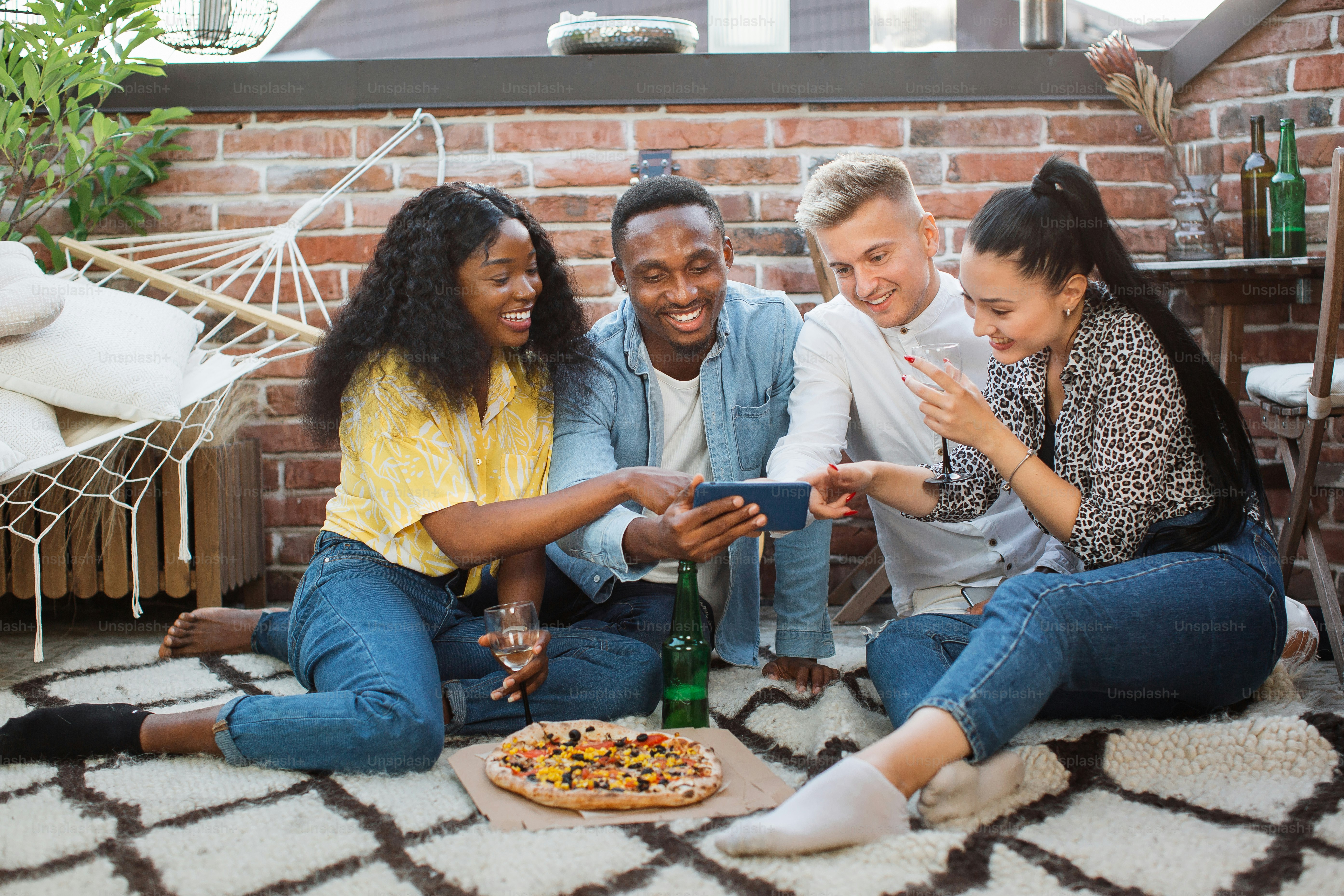 Multiethnische Gruppe von Freunden, die auf offener Terrasse mit ...