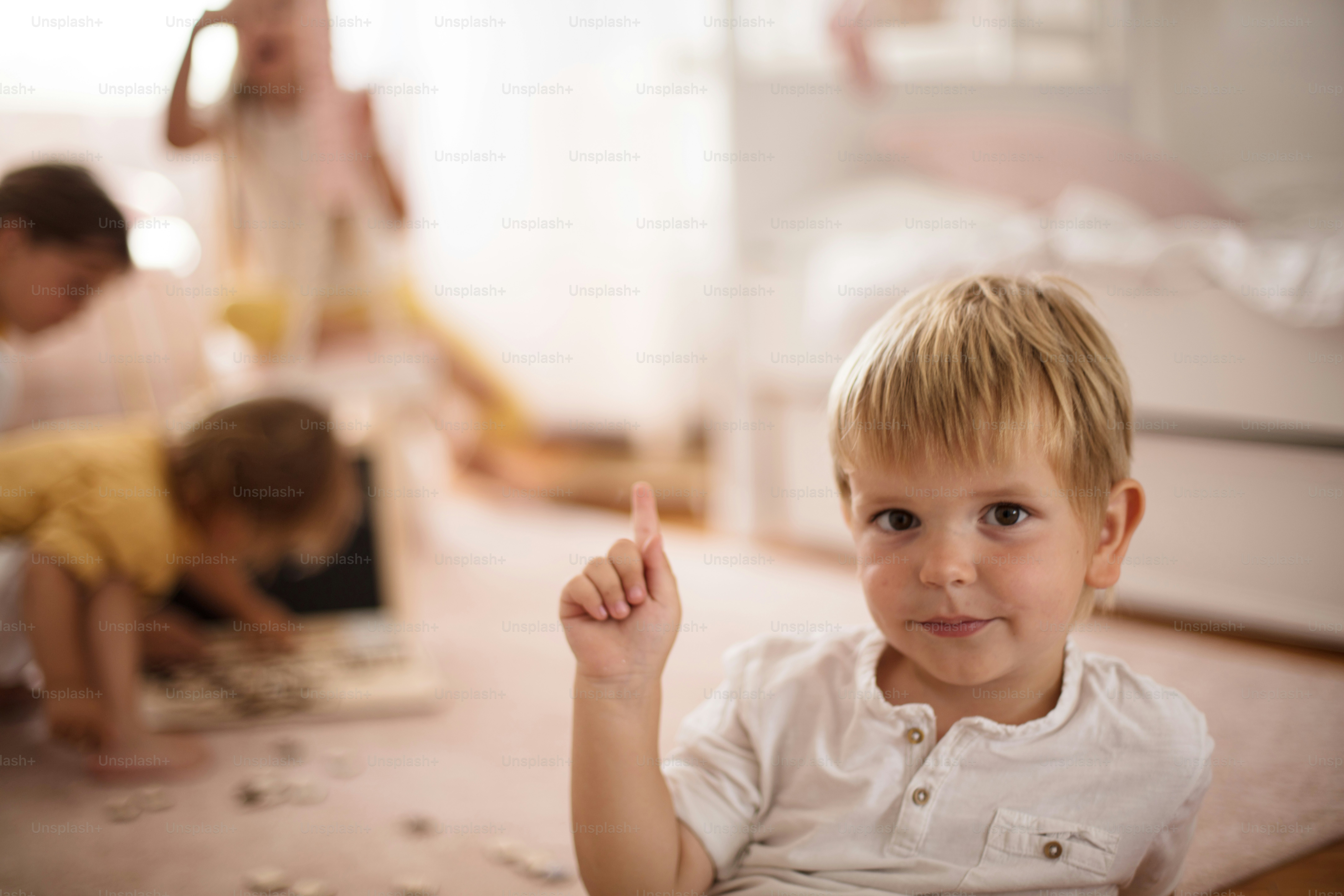 Little boy with finger up at home. Sitting in room and looking at ...