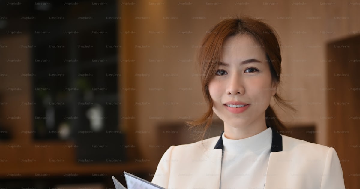 파일 폴더를 들고 현대 직장에 서 있는 동안 카메라를 향해 웃고 있는 여성 임원의 초상화 사진 Unsplash의 파일 폴더 이미지