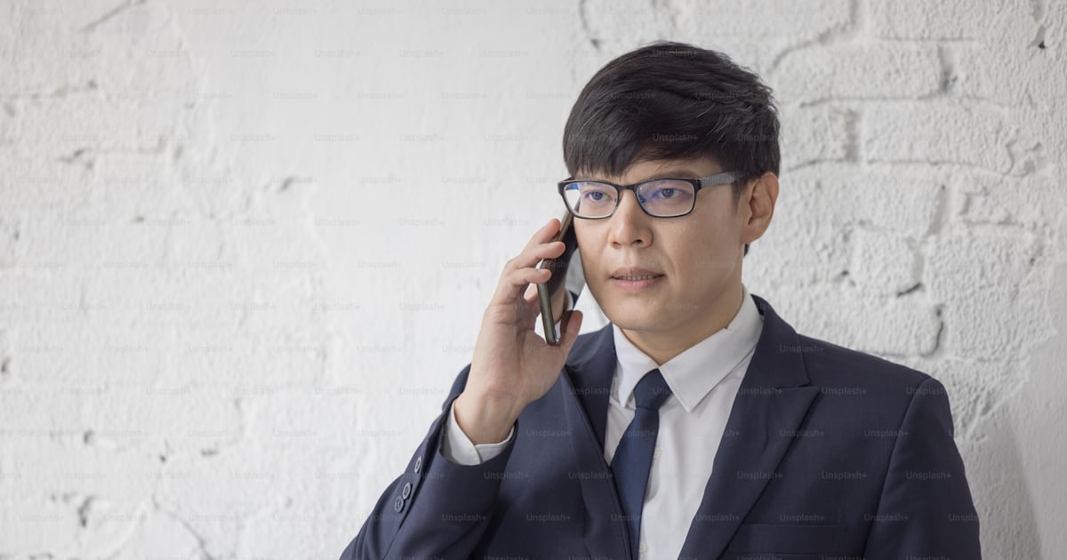 사업가가 사무실과 흰색 벽돌 벽 배경에서 핸드폰으로 이야기합니다 N 사진 Unsplash의 양복 이미지