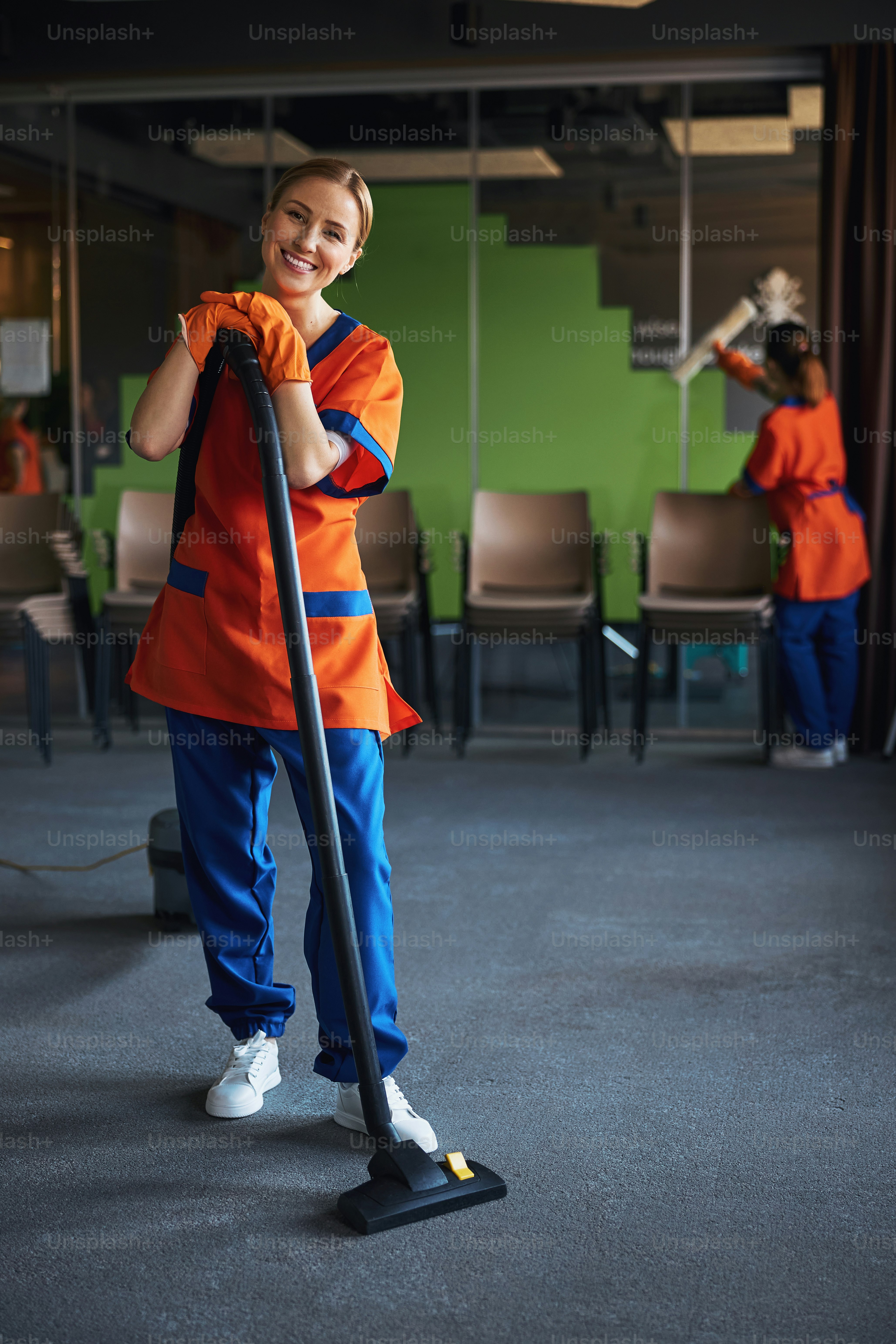 Full-length portrait of a cheerful worker leaning her hands on the ...