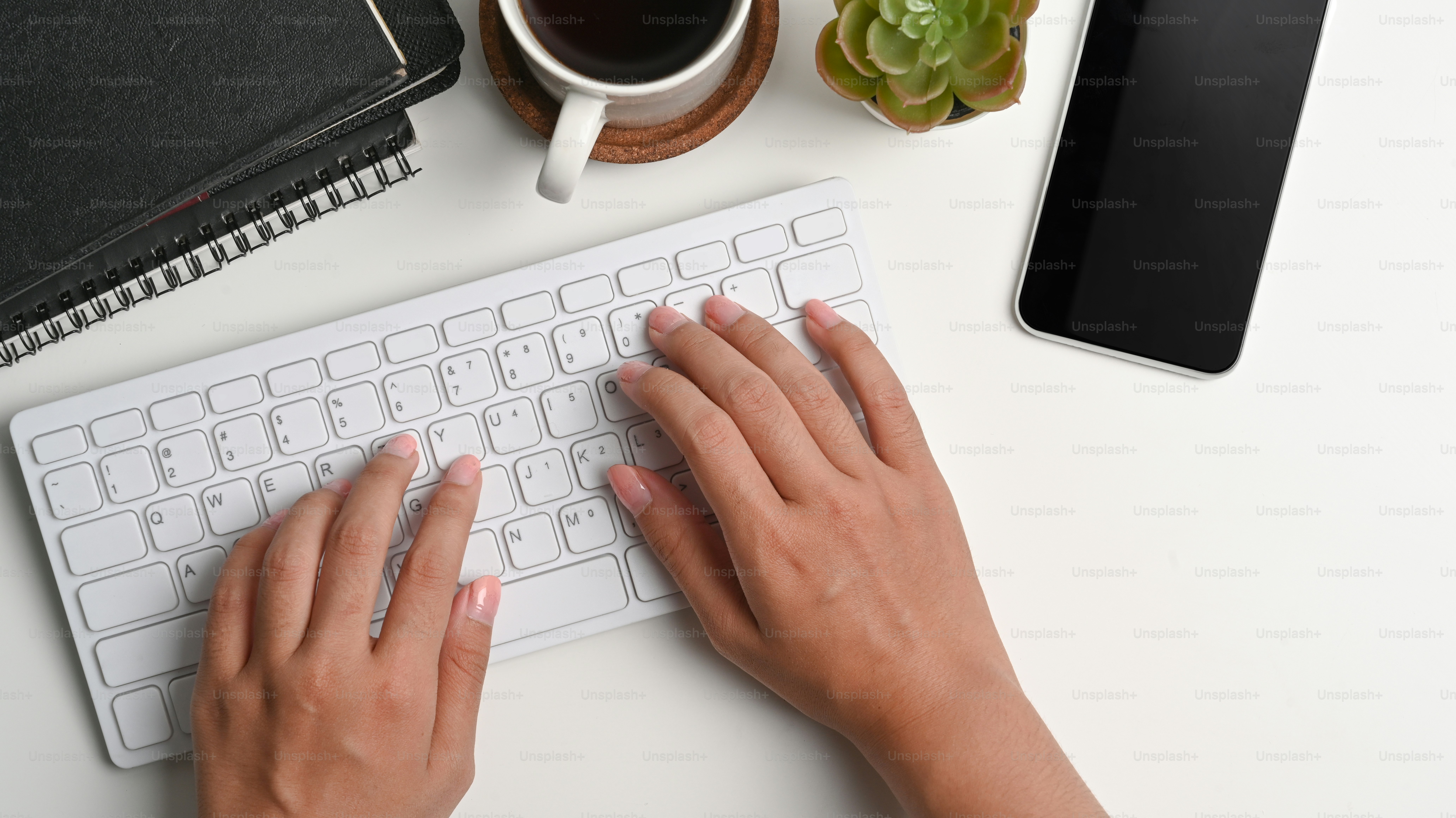 Above view of woman hands typing on keyboard over white office desk ...