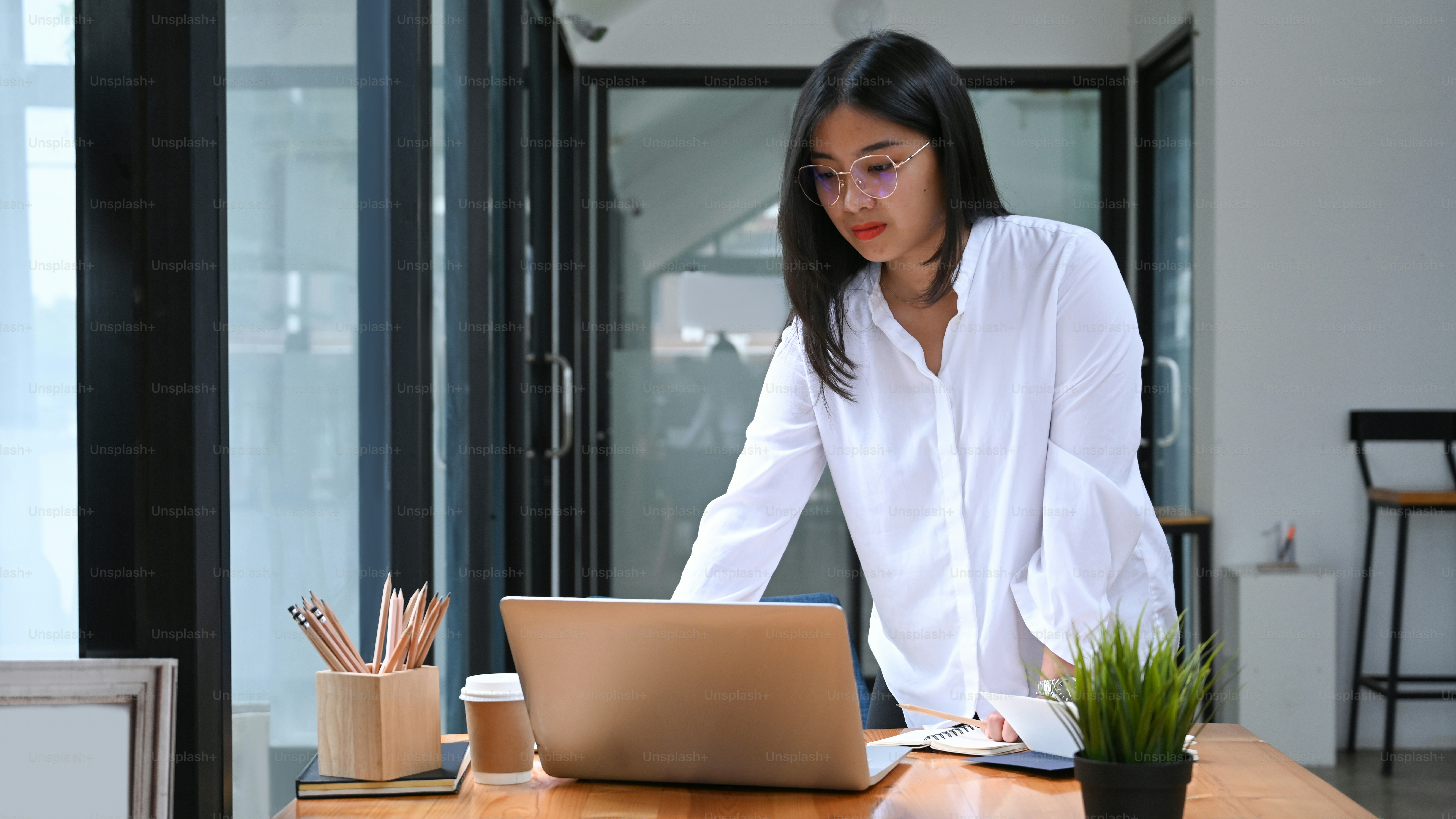 Young woman office worker standing and working on laptop computer at ...
