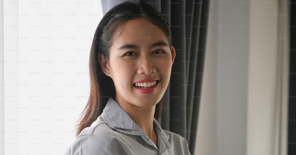 쾌활한 젊은 여성 직원이 파일 폴더를 들고 현대 직장에 서 있는 동안 카메라를 향해 웃고 있는 초상화 사진 Unsplash