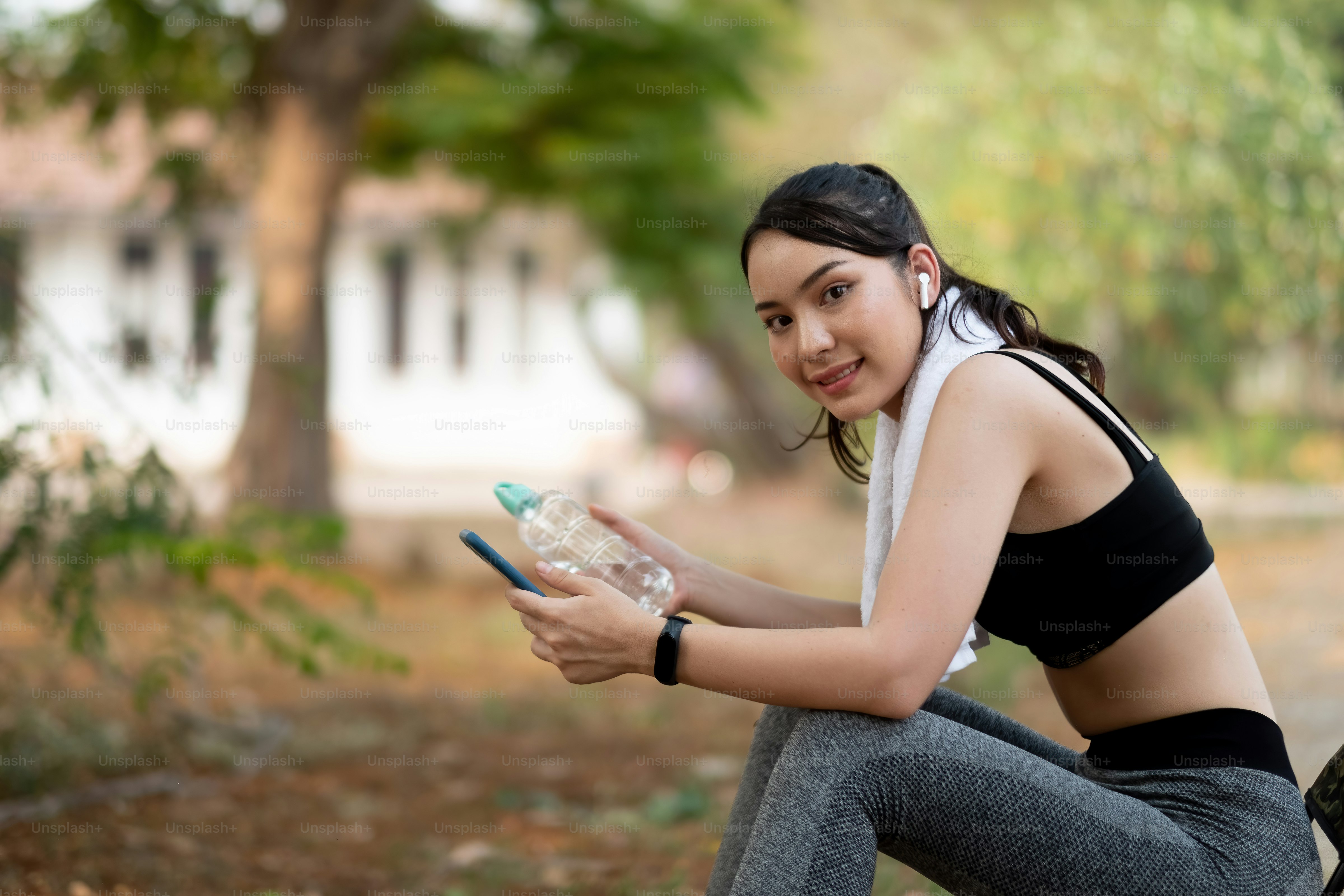 Tired fitness woman sweating taking a break listening to music on phone ...