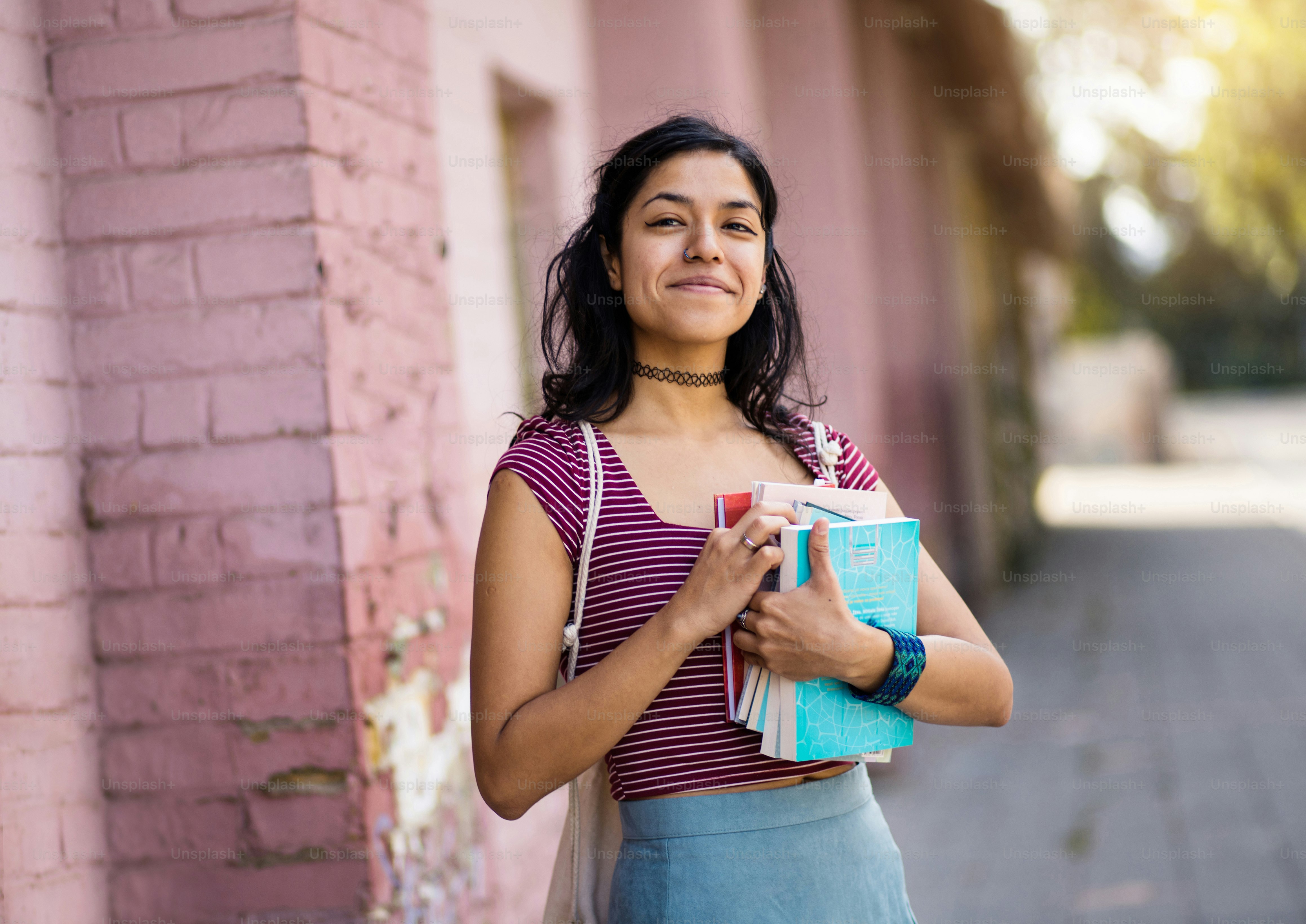 Young student woman standing on street and holding books. photo ...