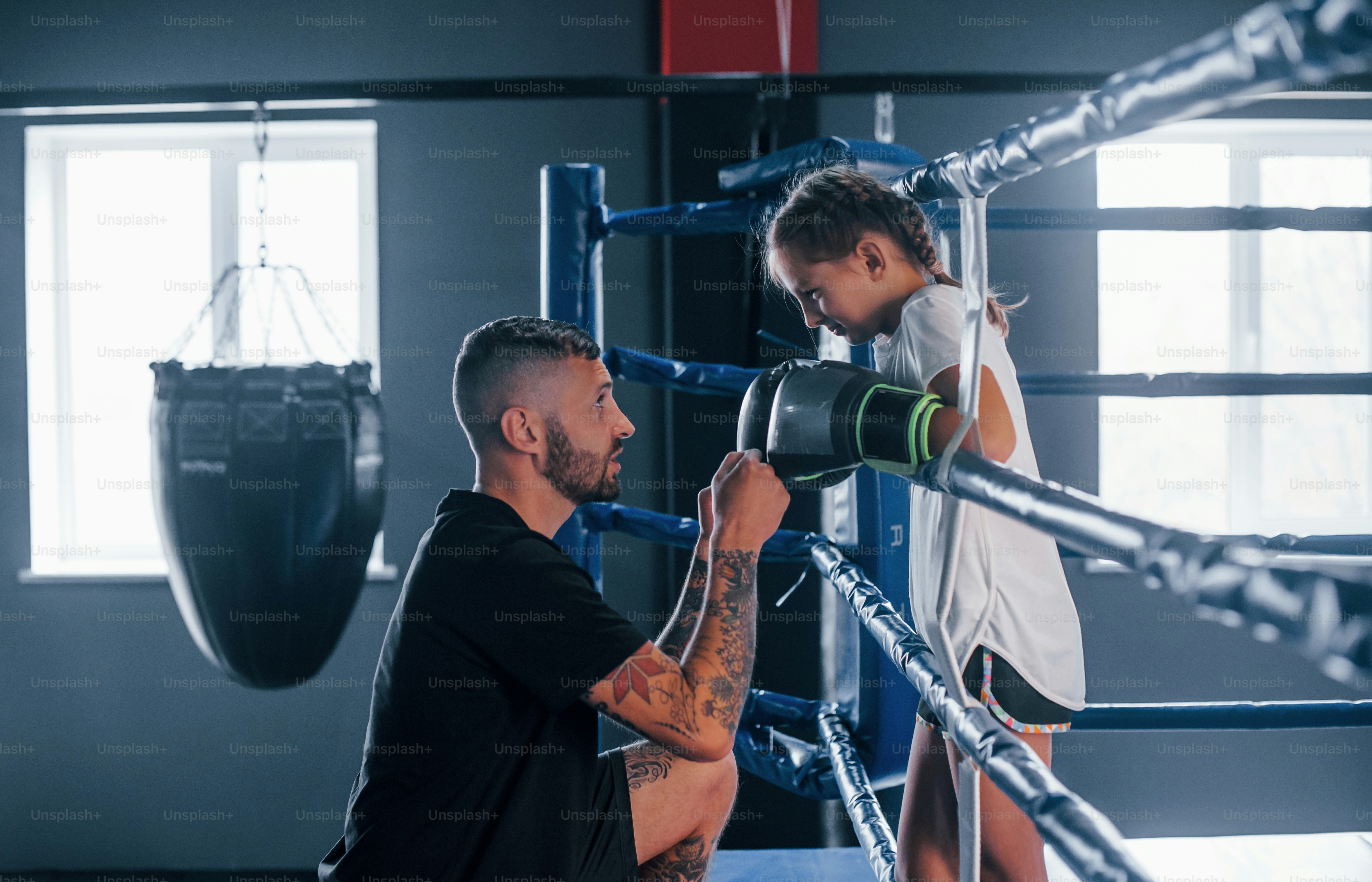 Conception of assistance. Young tattooed boxing coach teaches cute ...
