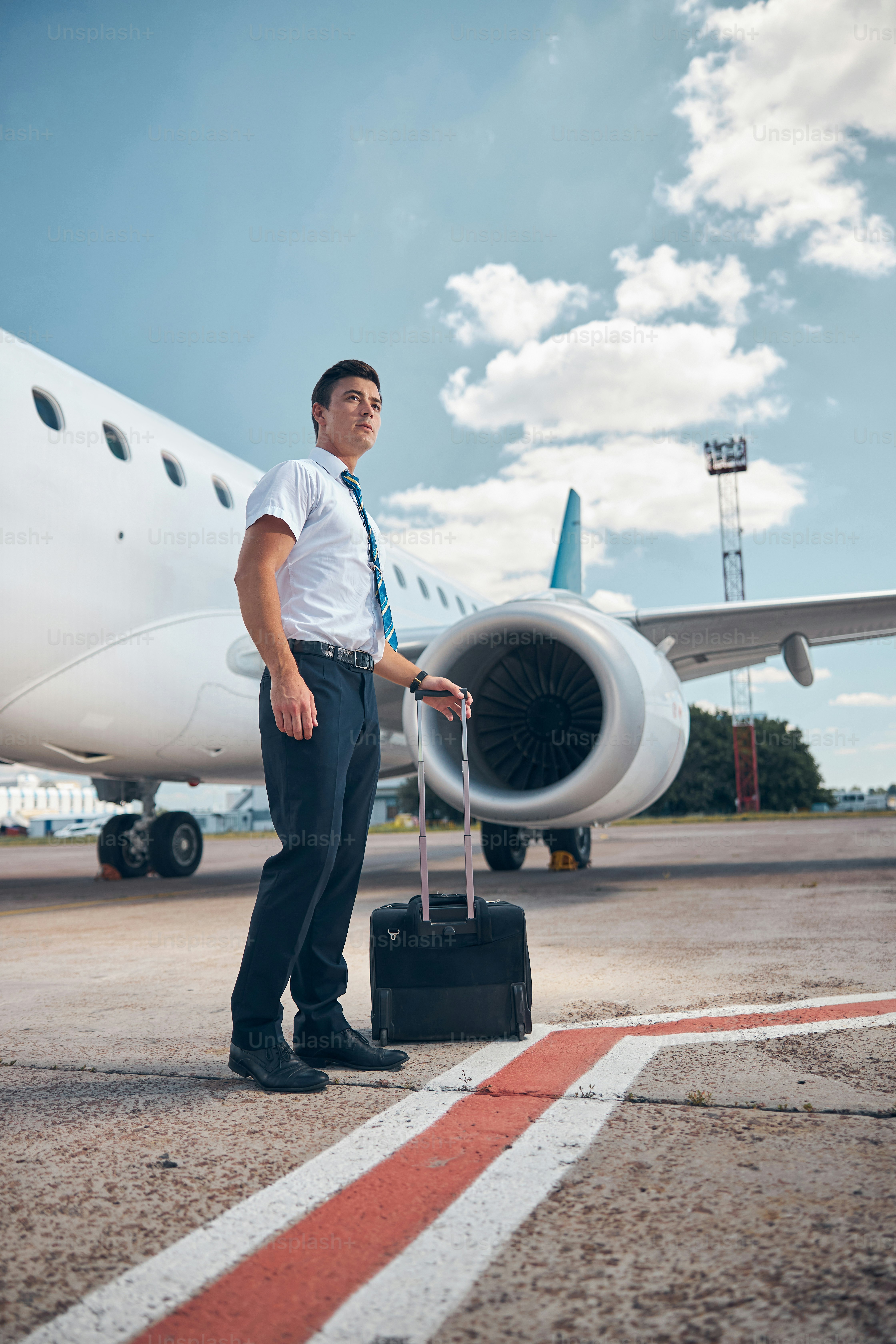 Handsome young man airline worker holding trolley luggage bag and ...