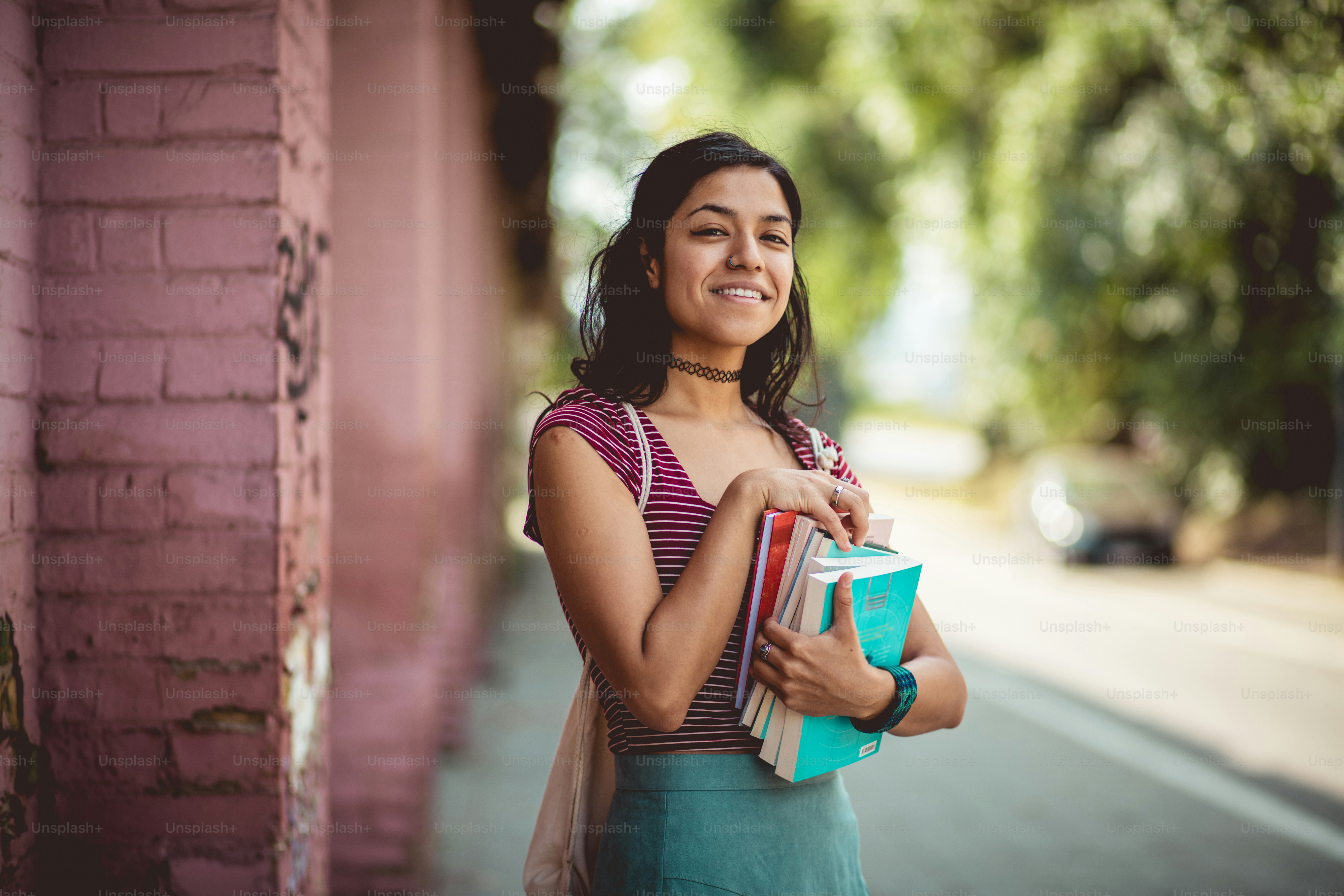 Young student woman standing on street and holding books. photo ...