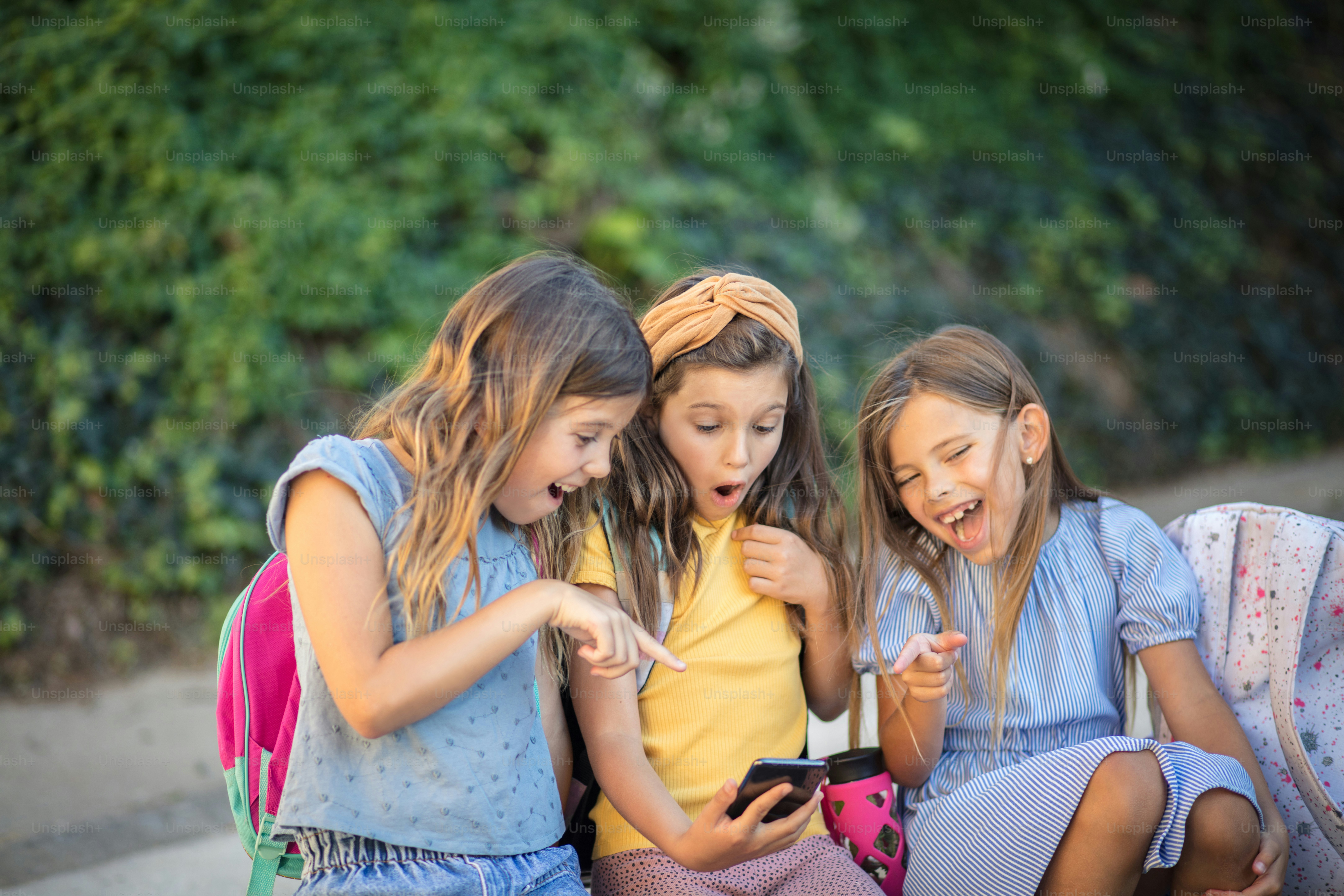 Childhood in the digital age. Three little girls playing outside. photo ...