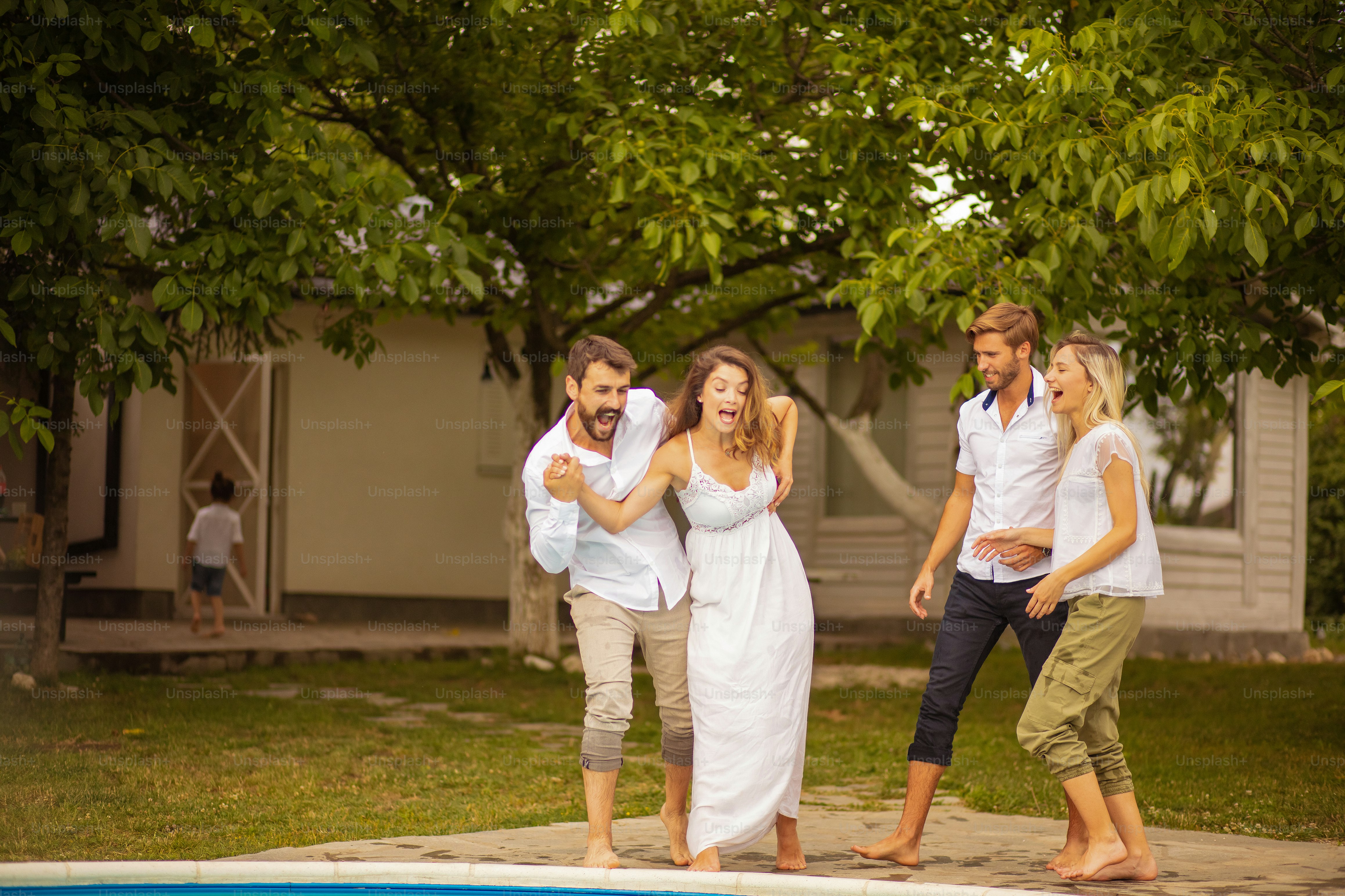 Group of young people by the swimming pool. Friends having fun by the ...