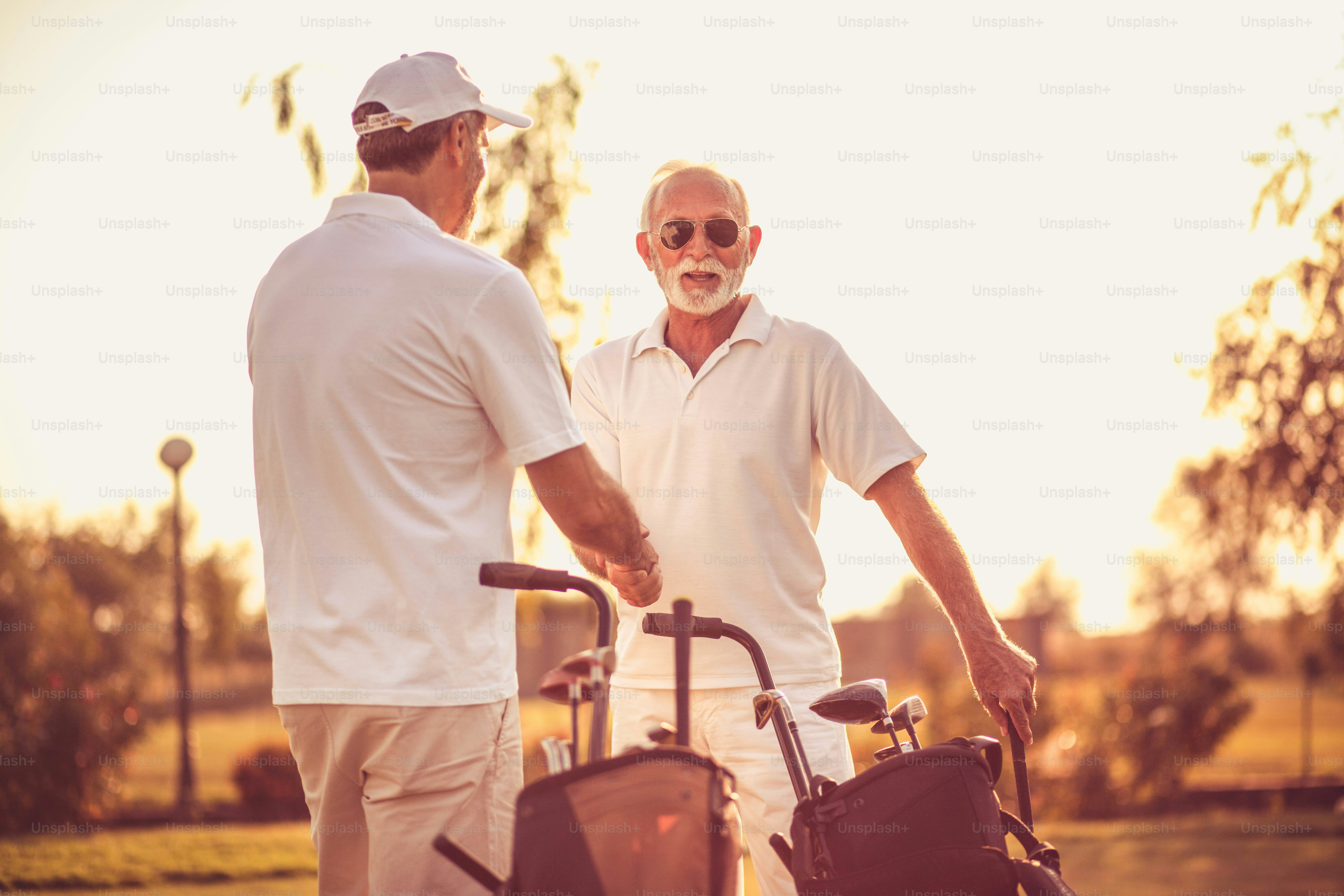Foto Dua pria senior di lapangan golf mereka berjabat tangan. – Gambar ...