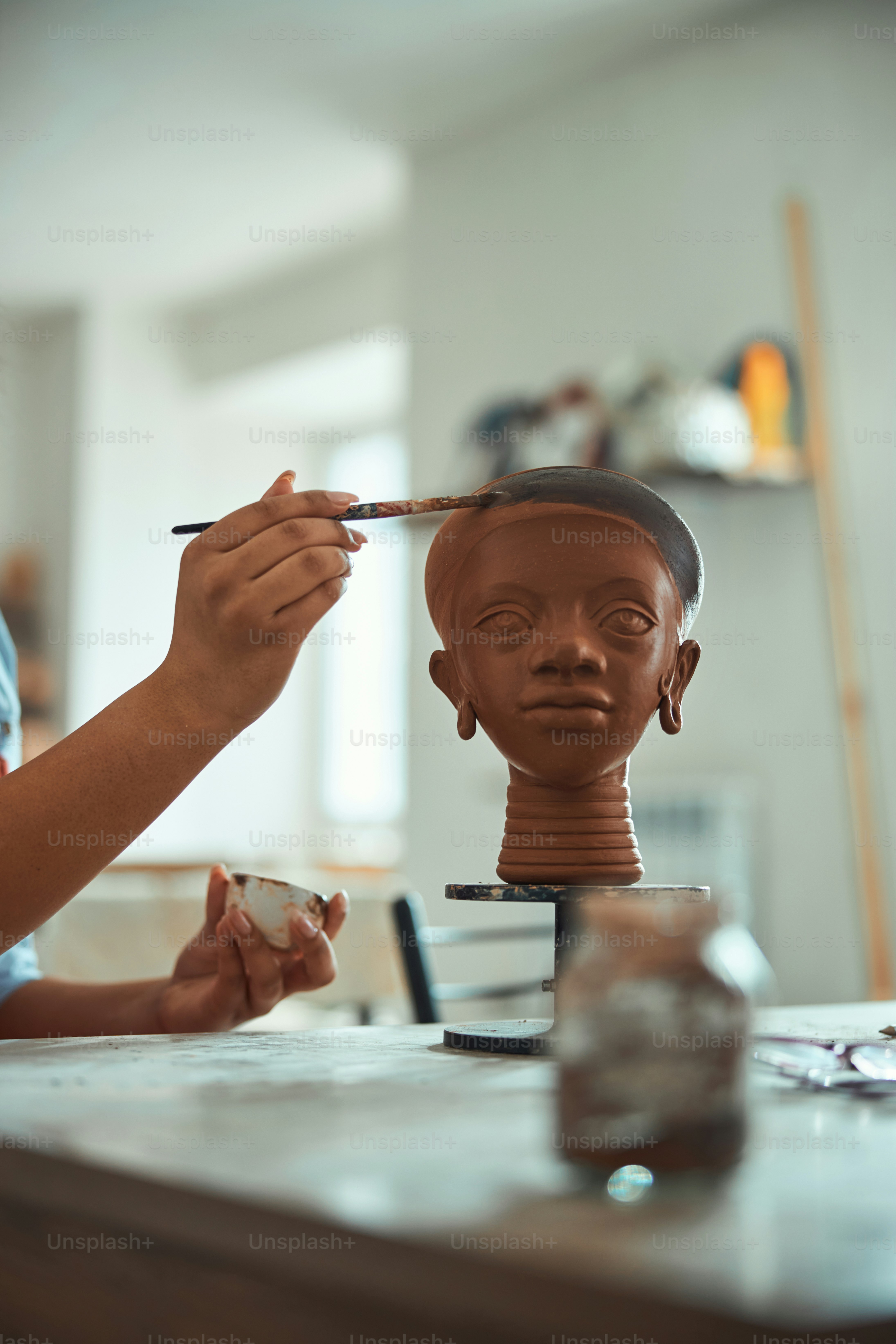 Primer plano de la joven artista de cerámica que pinta en la escultura ...