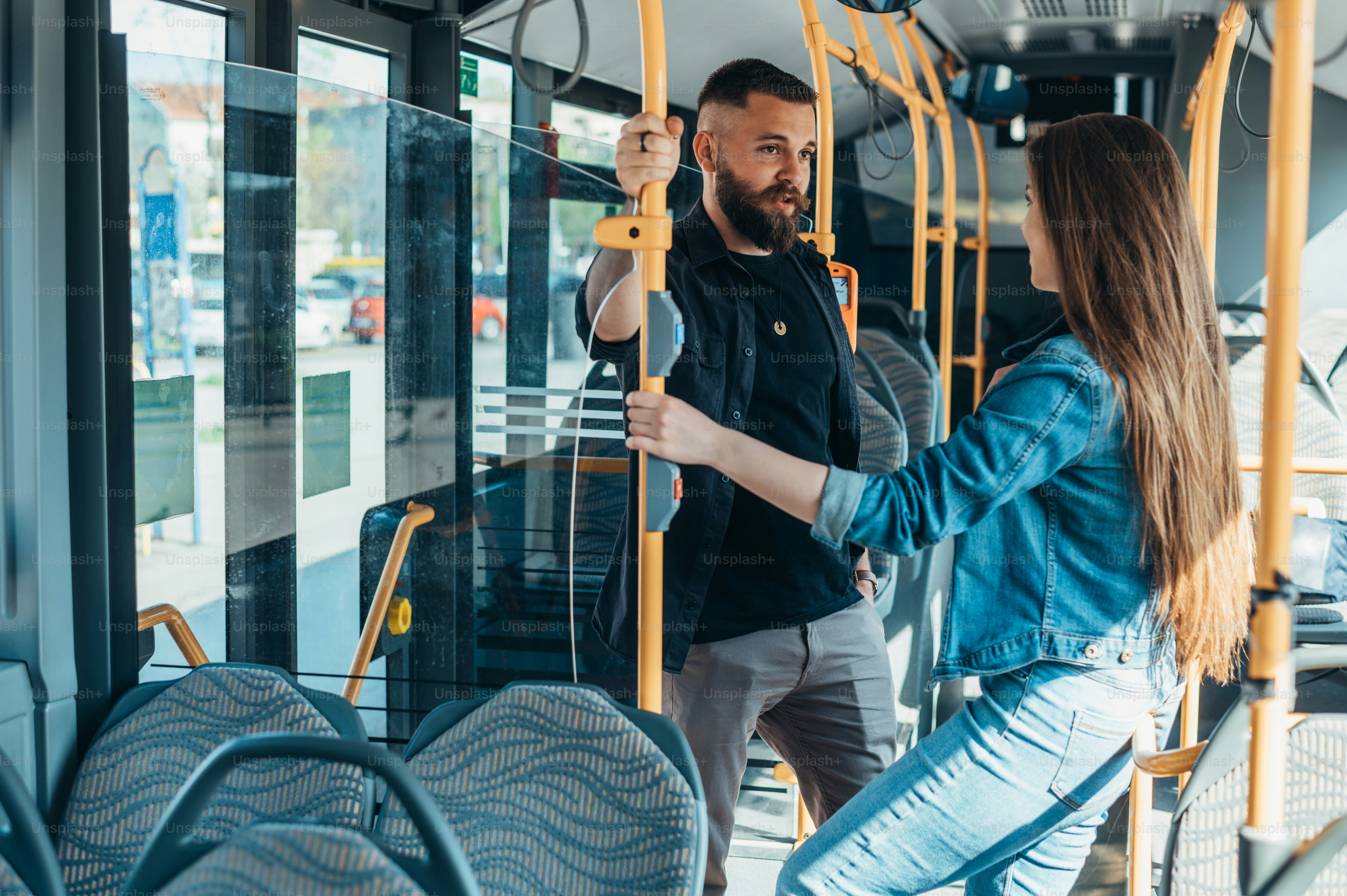 Beautiful couple standing in a moving bus and talking and flirting ...