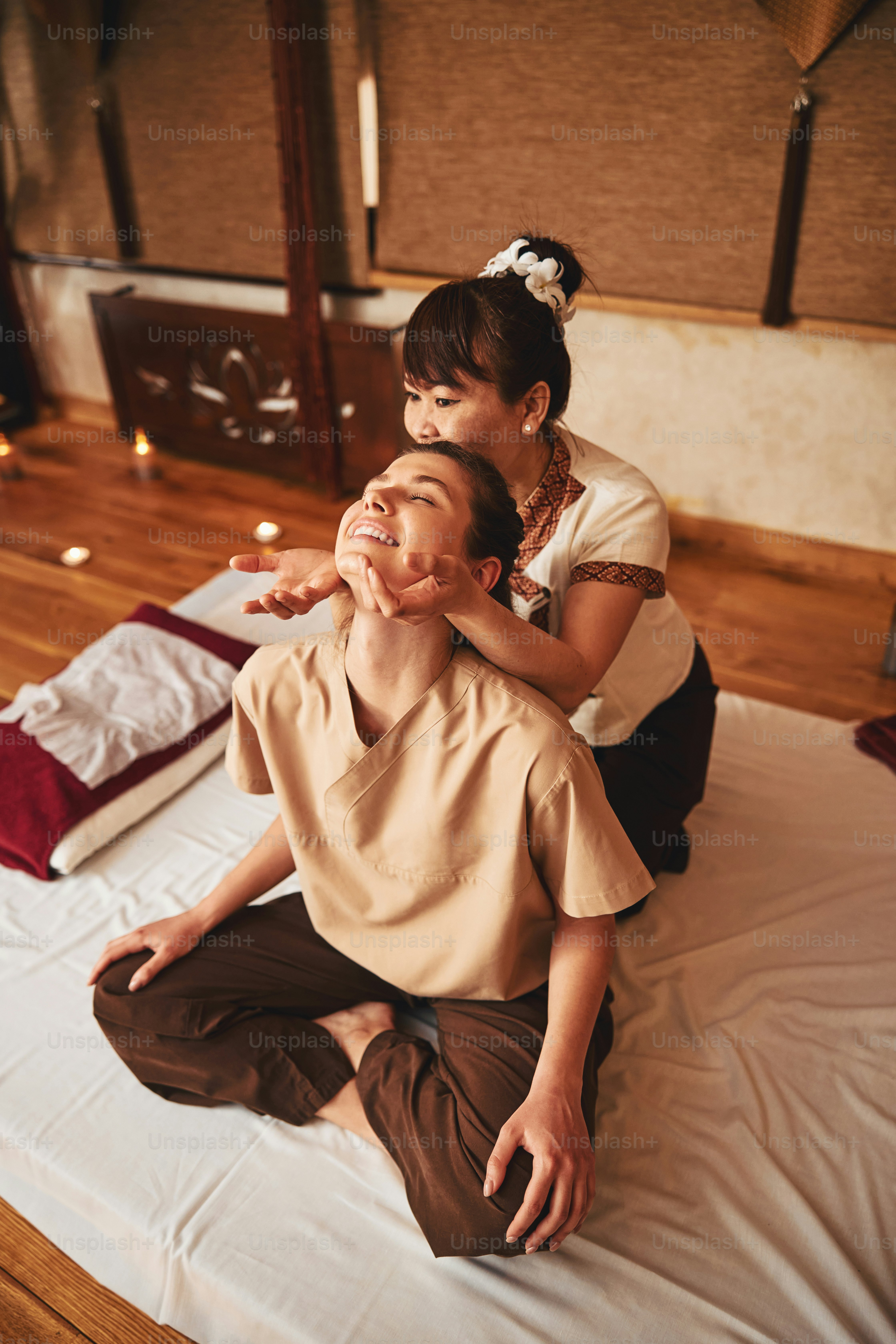 Thai massage worker putting her hands on both sides of female neck and ...