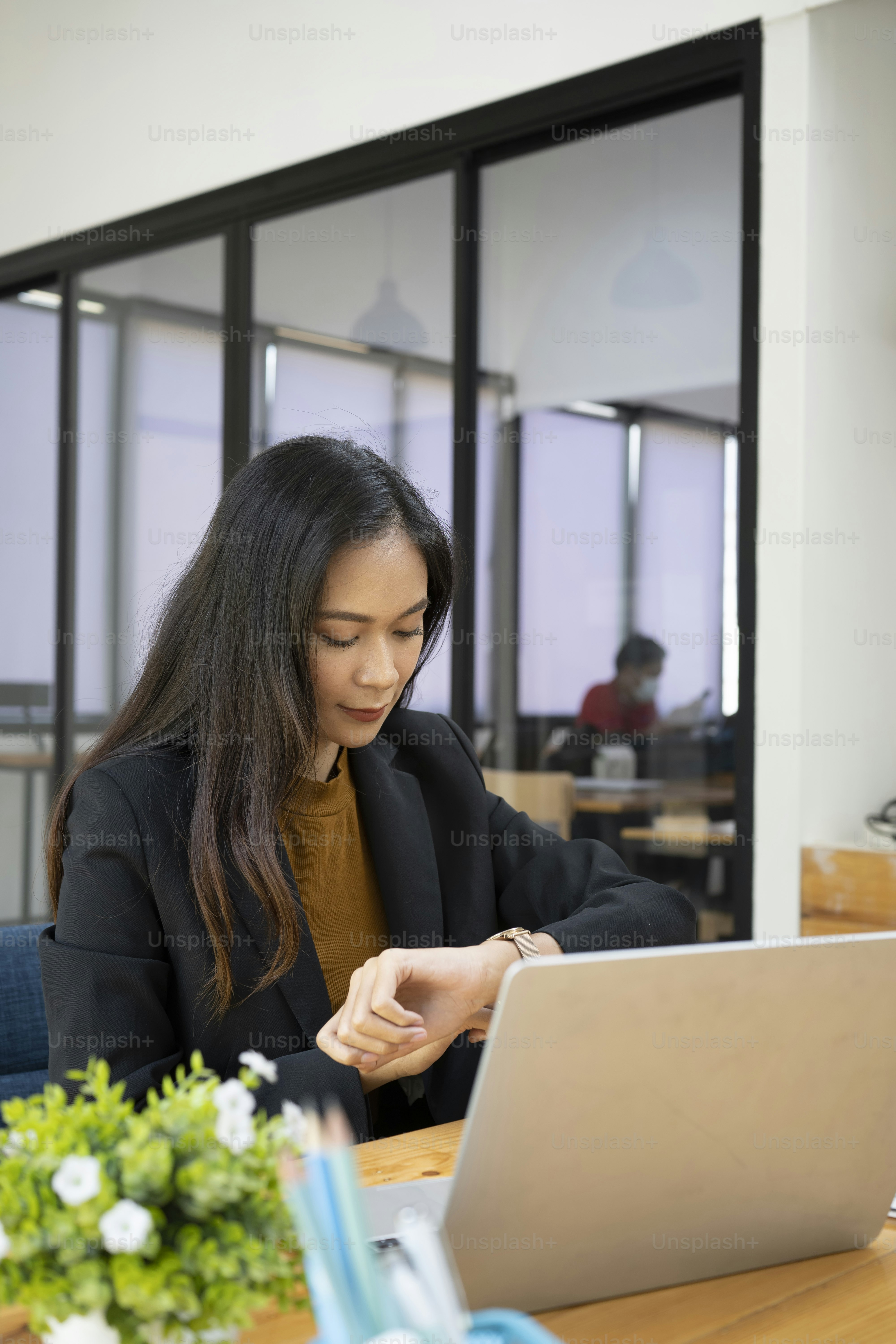 Businesswoman checking time on her wrist watch while sitting in office ...