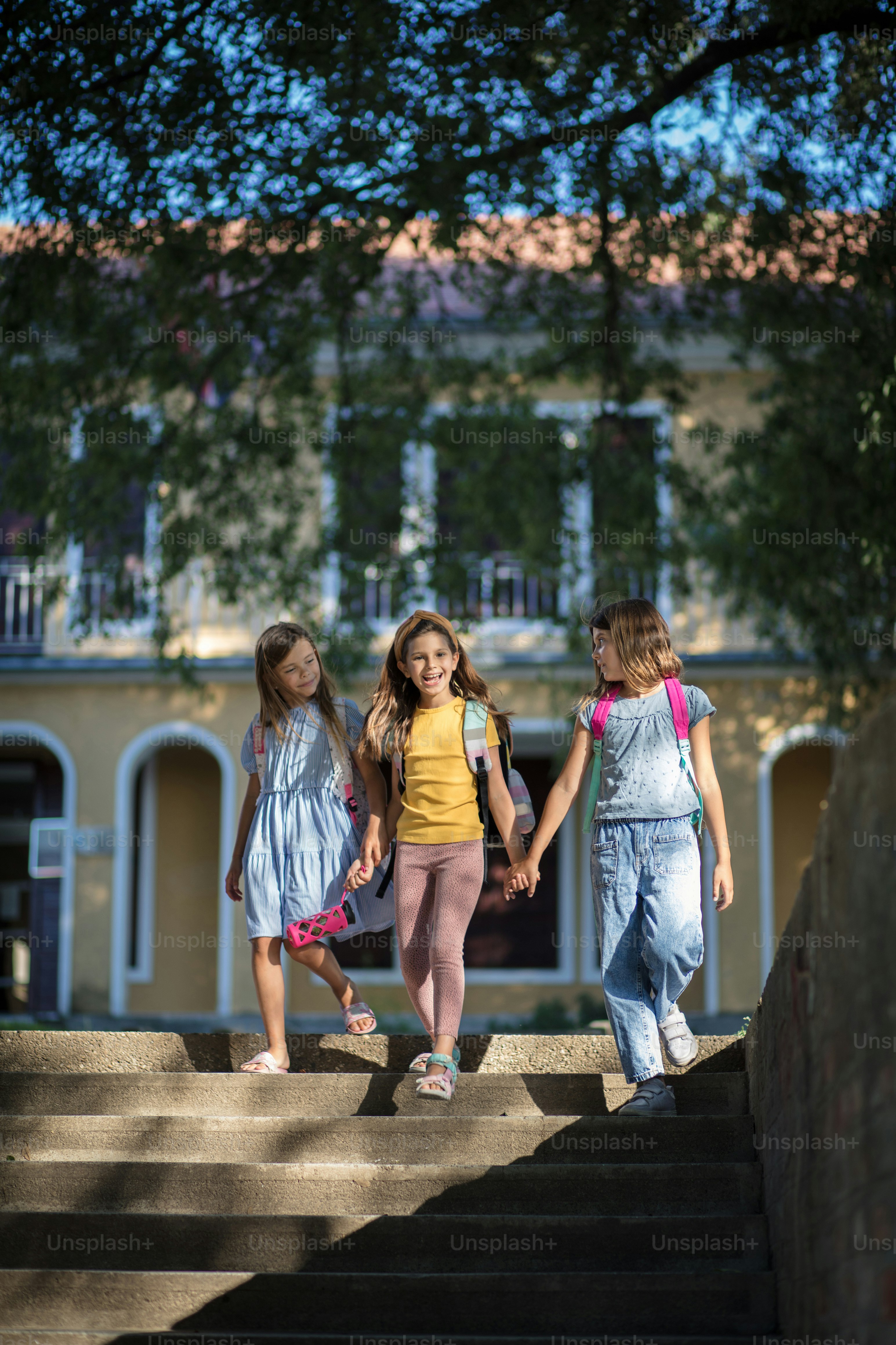 Three little school girls leaving school together. photo – Outdoor ...