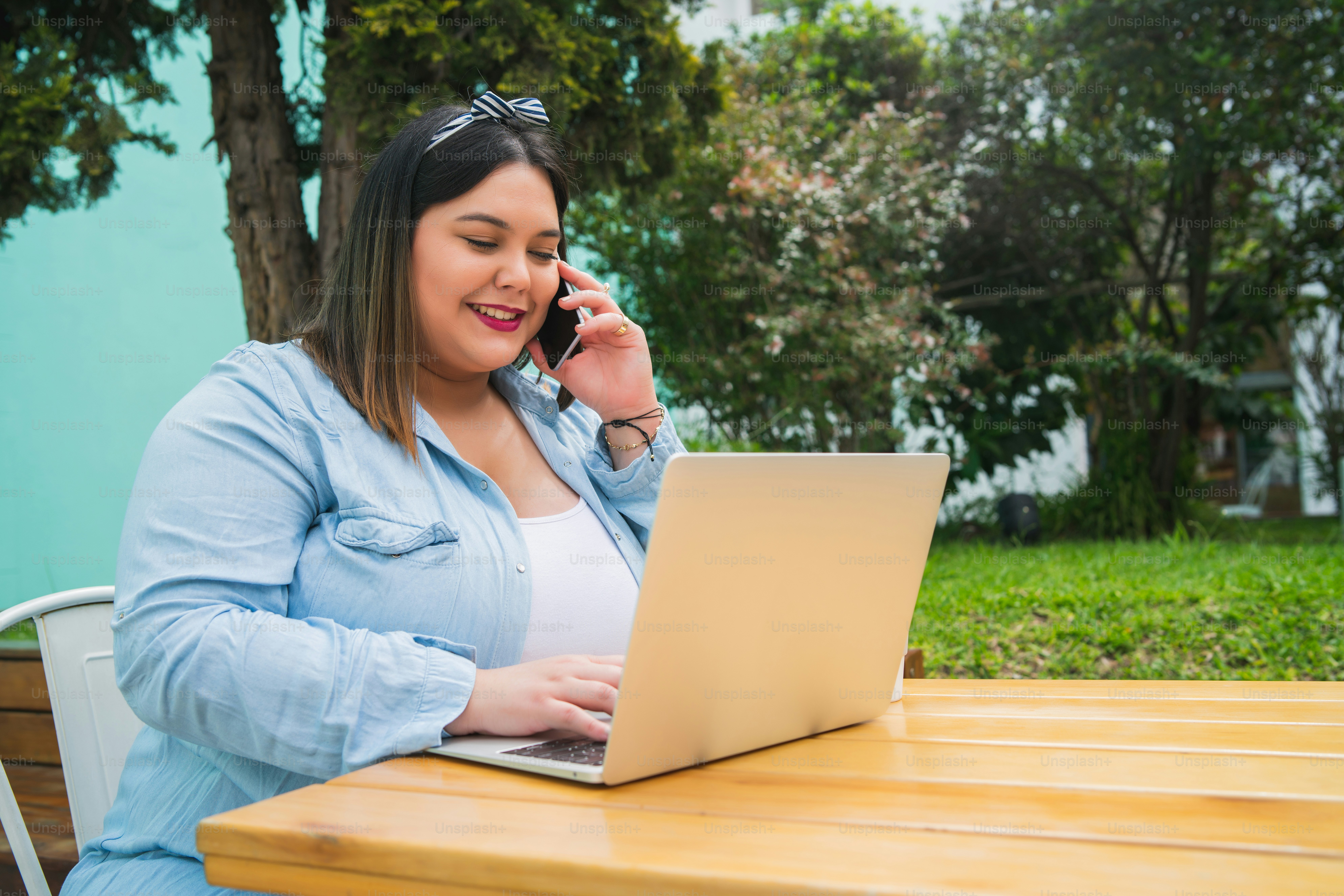 Portrait of young pluse size woman using her laptop and talking on the ...