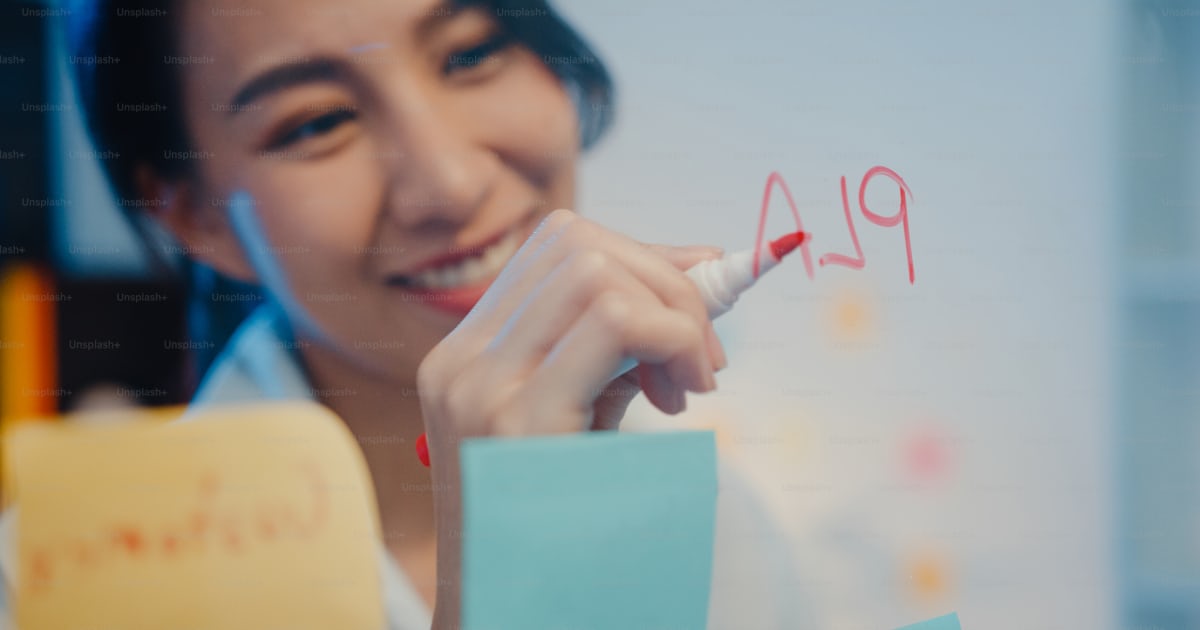 아시아 사업가들은 투명한 유리 벽 뒤에 서서 진행 상황을 가리키는 관리자의 말을 듣고 회의를 브레인스토밍하고 작업자는 벽에