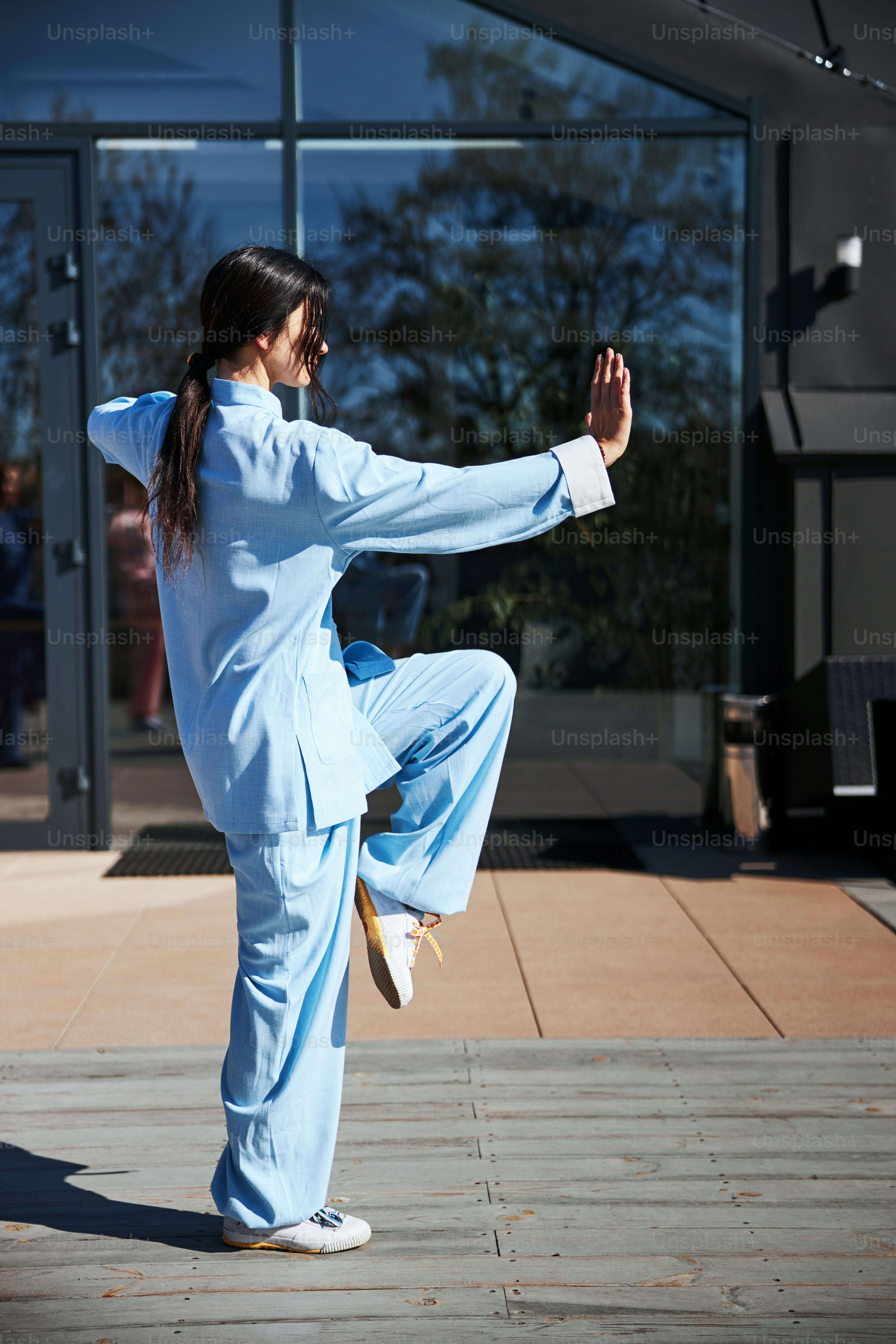 Concentrated woman in Chinese suit standing on one foot and putting her ...