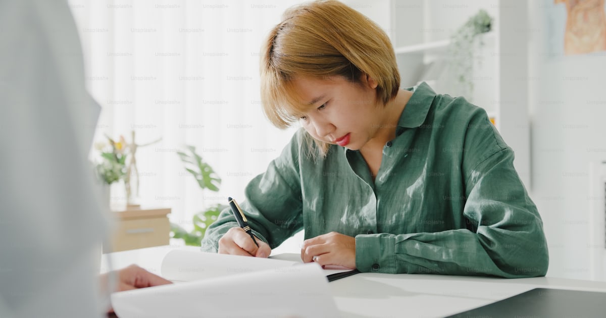 젊은 아시아 소녀 여성 환자가 의료 양식 또는 서명 건강 보험 계약에 서명하고 건강 병원 사무실의 책상에 앉아 있는 흰색 의료