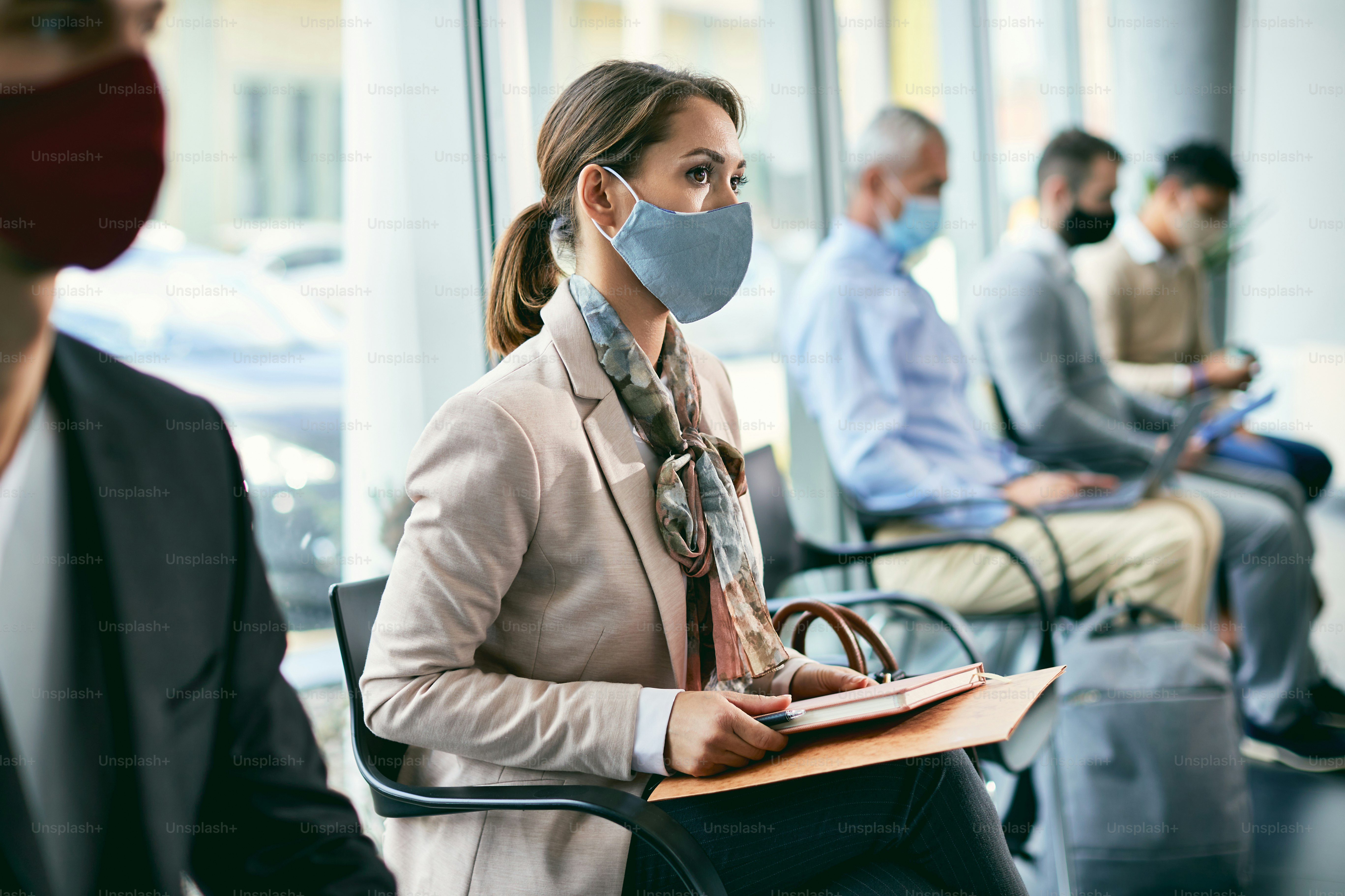 Young business woman wearing protective face mask while waiting for job ...