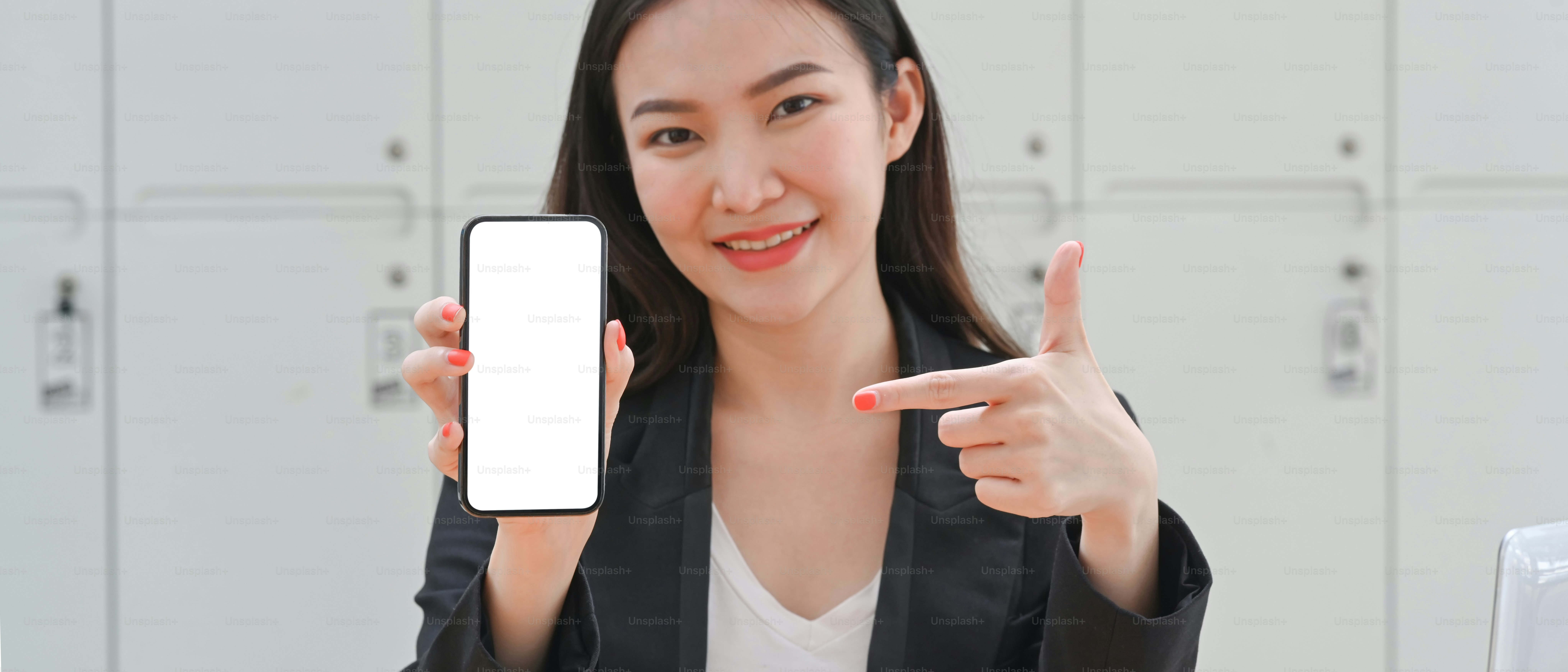 Smiling businesswoman holding and showing mock up mobile phone with ...