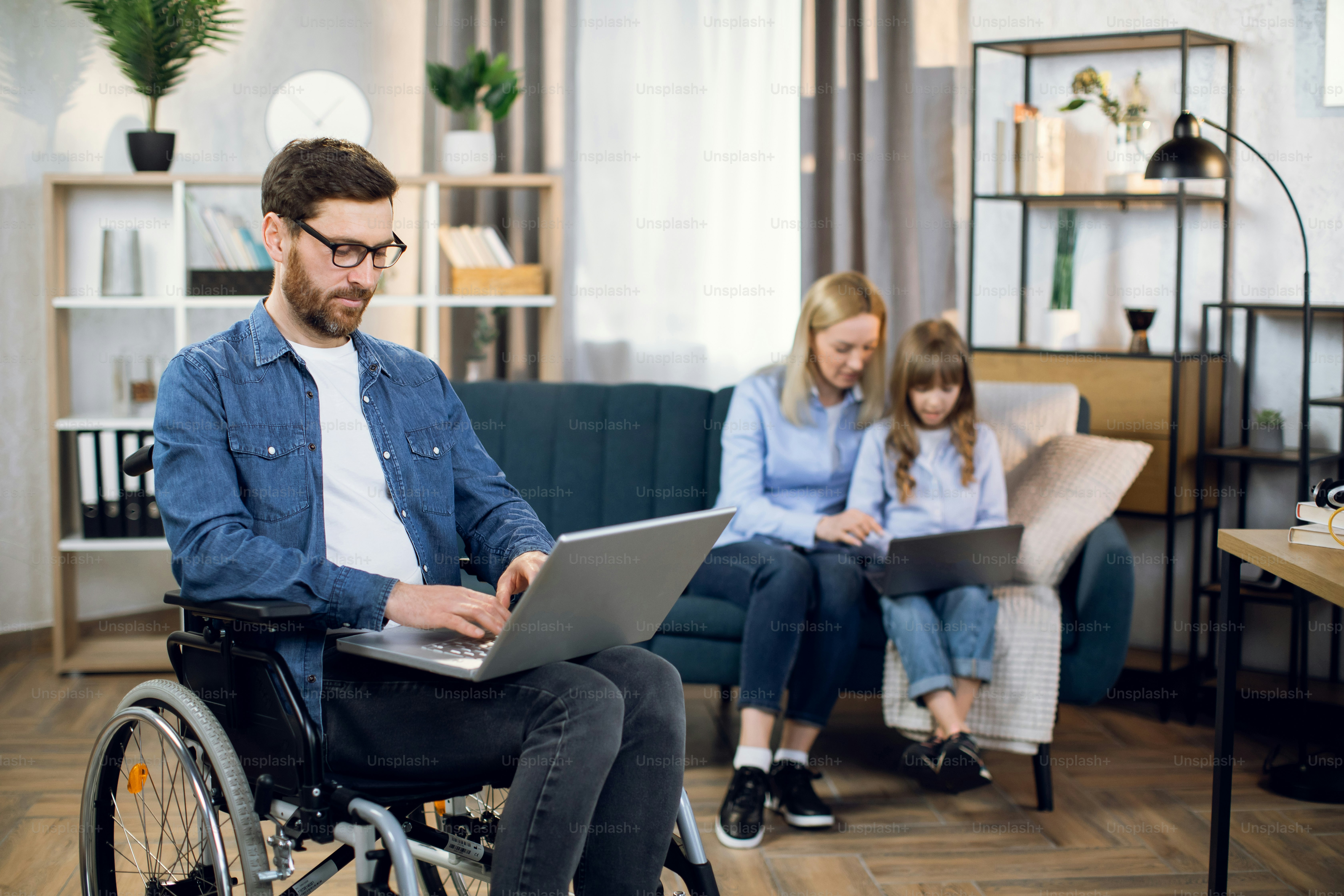 Disabled bearded man working on modern laptop while his wife and ...