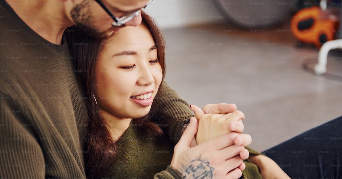 캐주얼한 옷을 입은 행복한 다민족 커플이 스튜디오 실내에 함께 앉아 있다 아시아 여자 친구와 백인 남자 사진