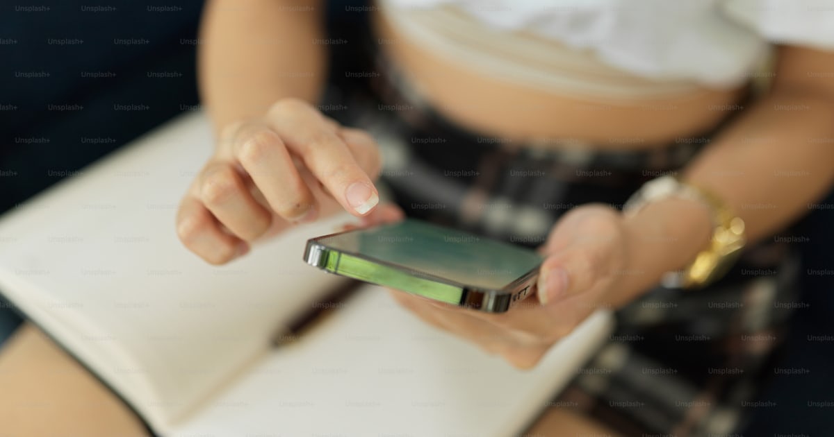 職場に座りながらスマートフォンを使う若い女性の手のトップビューの写真 指 Unsplashの写真