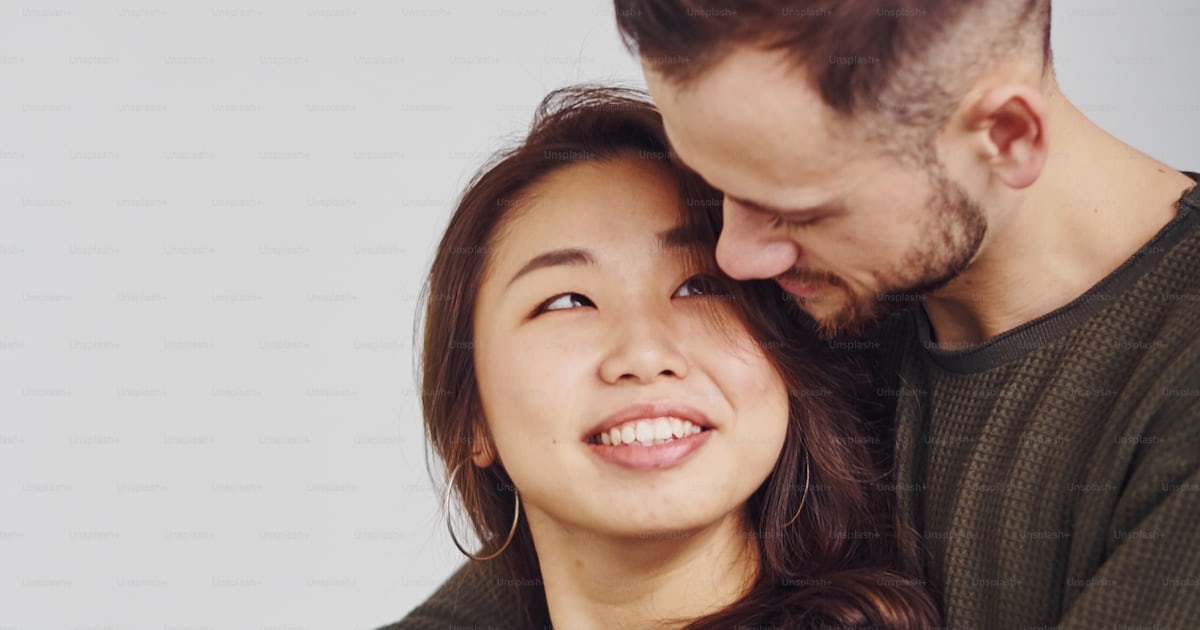 캐주얼한 옷을 입은 행복한 다민족 커플이 스튜디오 실내에서 서로를 껴안고 있다 아시아 여자 친구와 백인 남자 사진