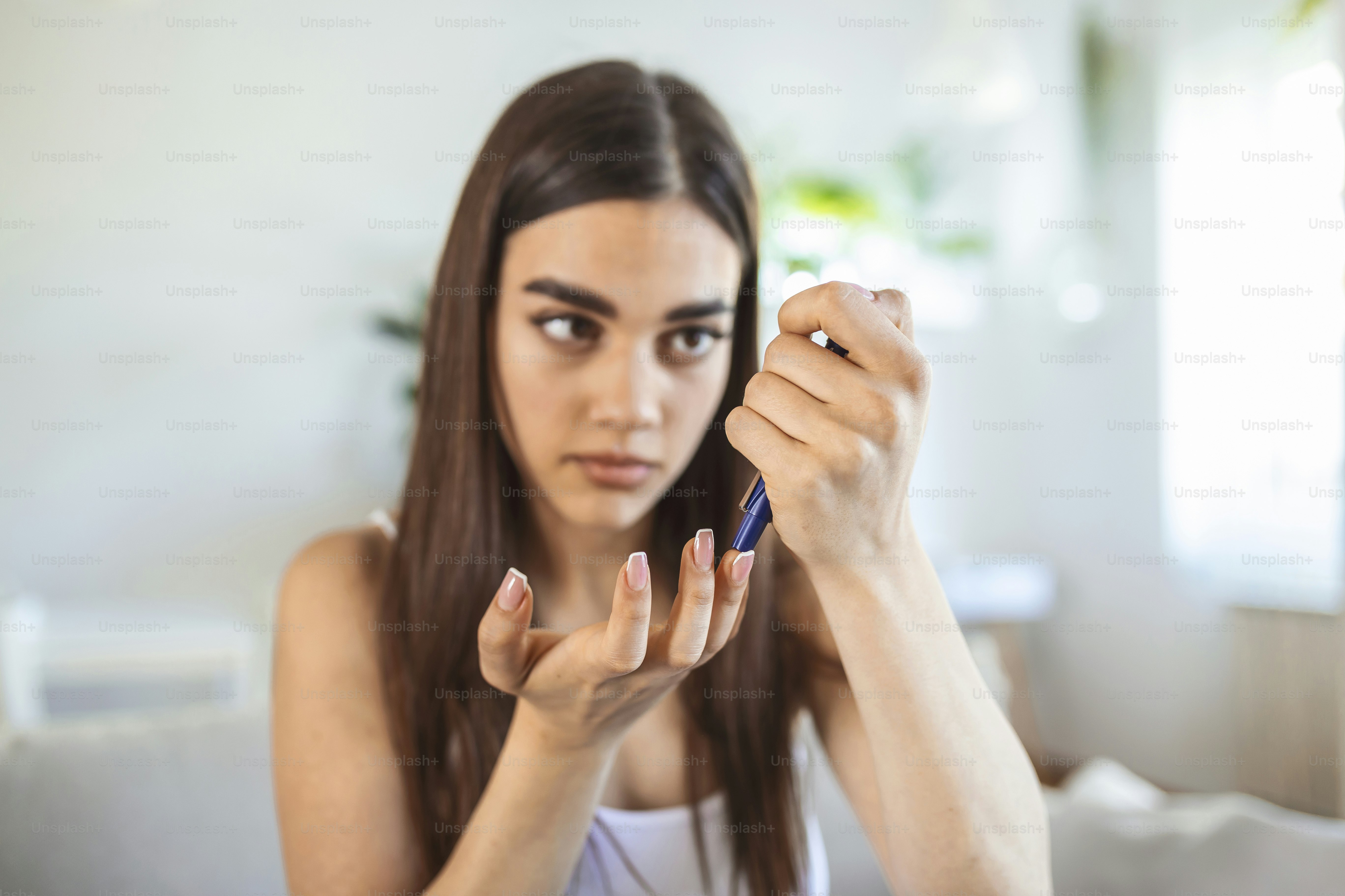 Woman using lancelet on finger. woman doing blood sugar test at home in ...