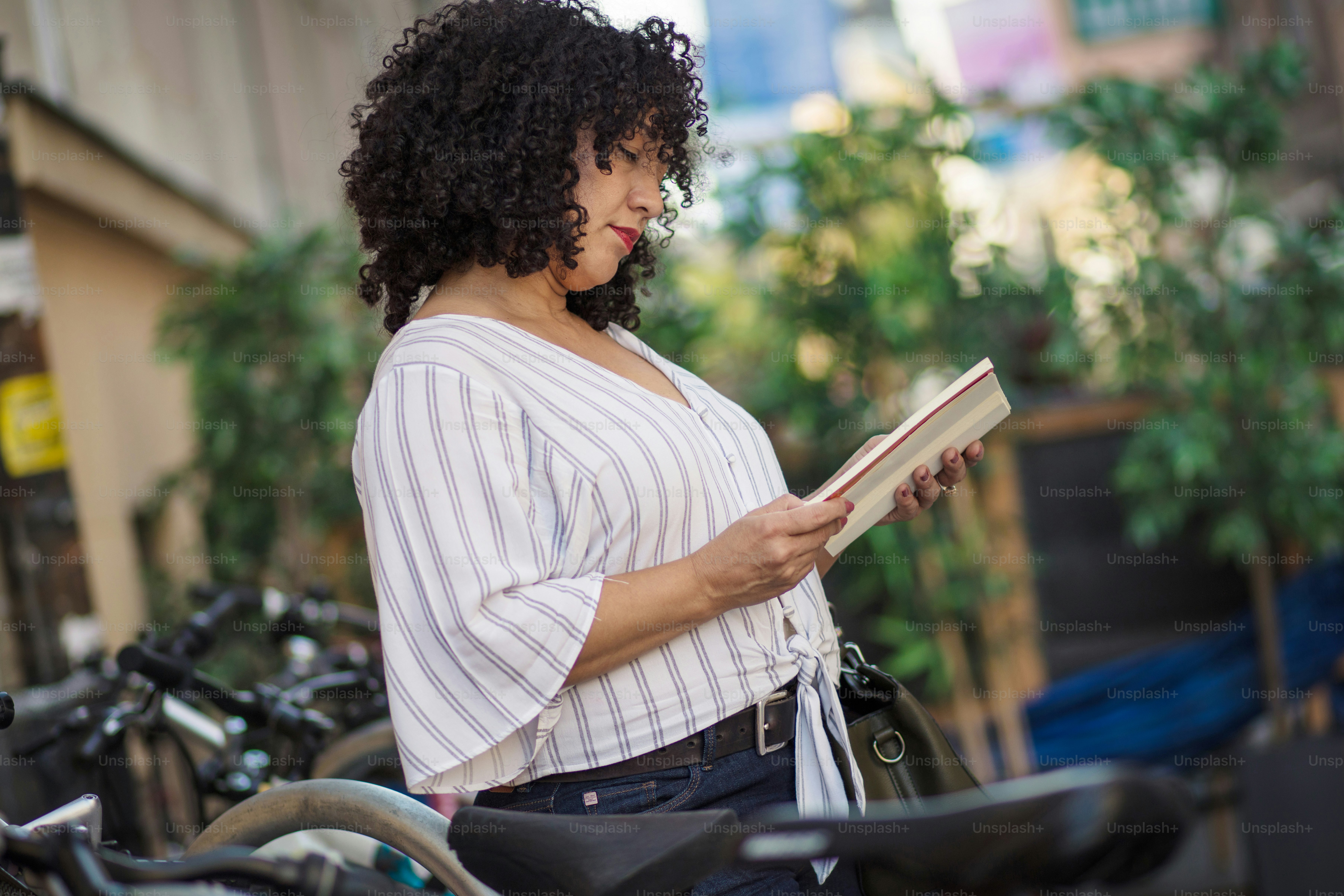Good book. Black adult woman reading story book in downtown city. Woman ...