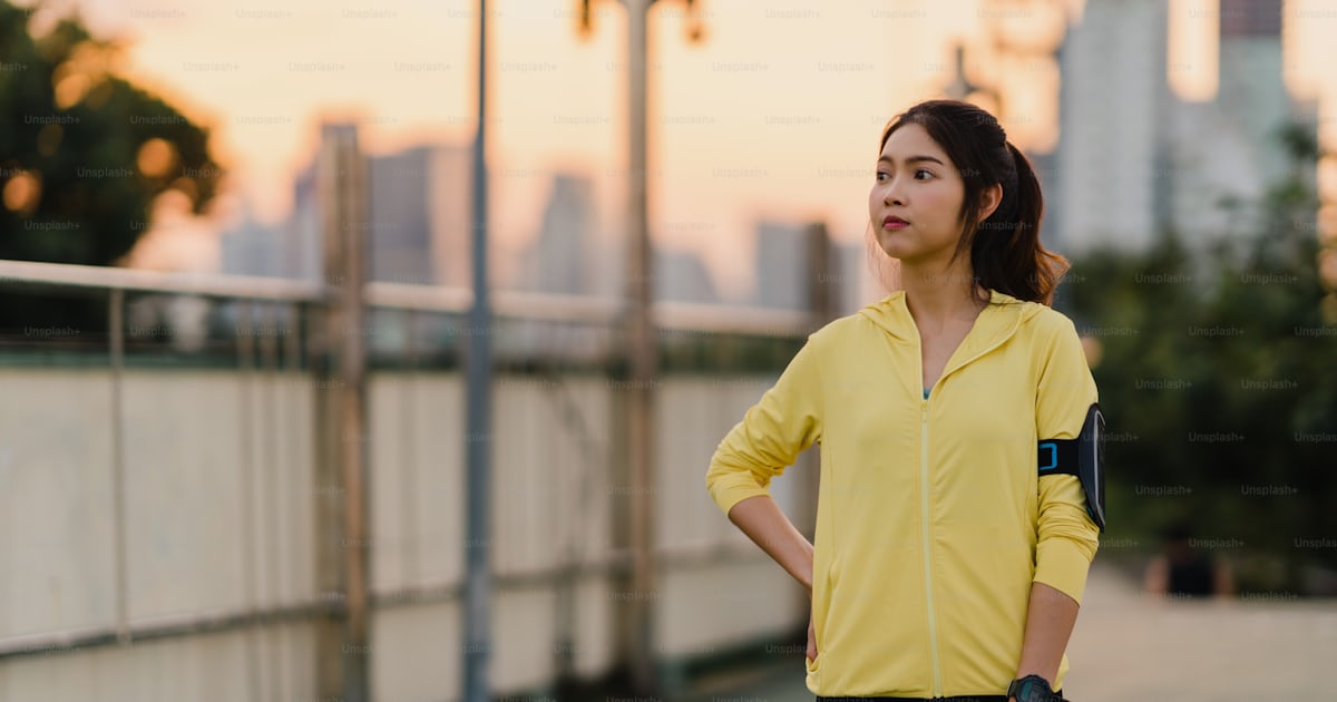 아름 다운 젊은 아시아 운동 선수 아가씨는 도시 환경에서 스트레칭 운동을합니다 이른 아침에 보도 다리에서 운동복을 입은 일본