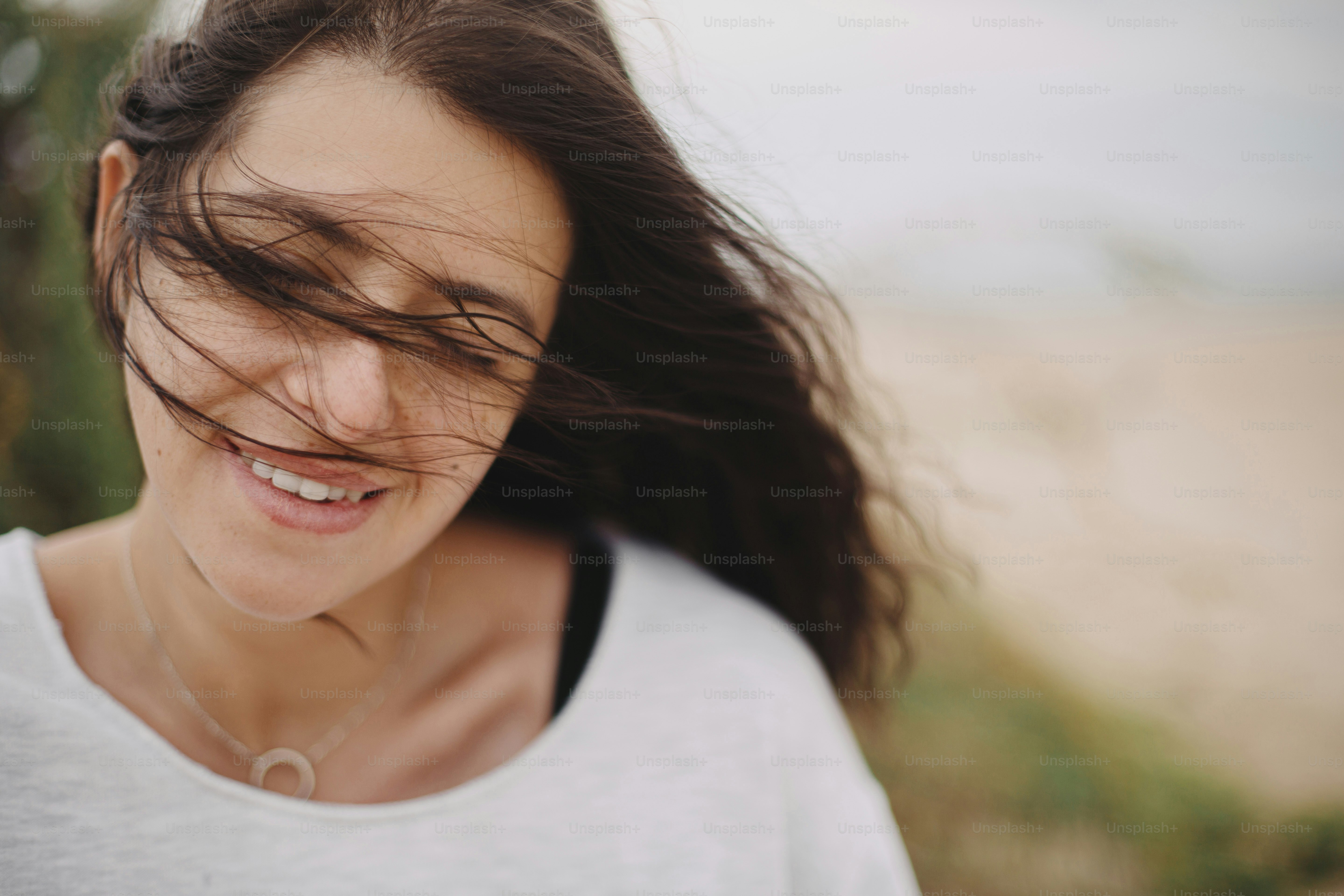 Beautiful happy woman with windy hair sitting on sandy beach at sea ...