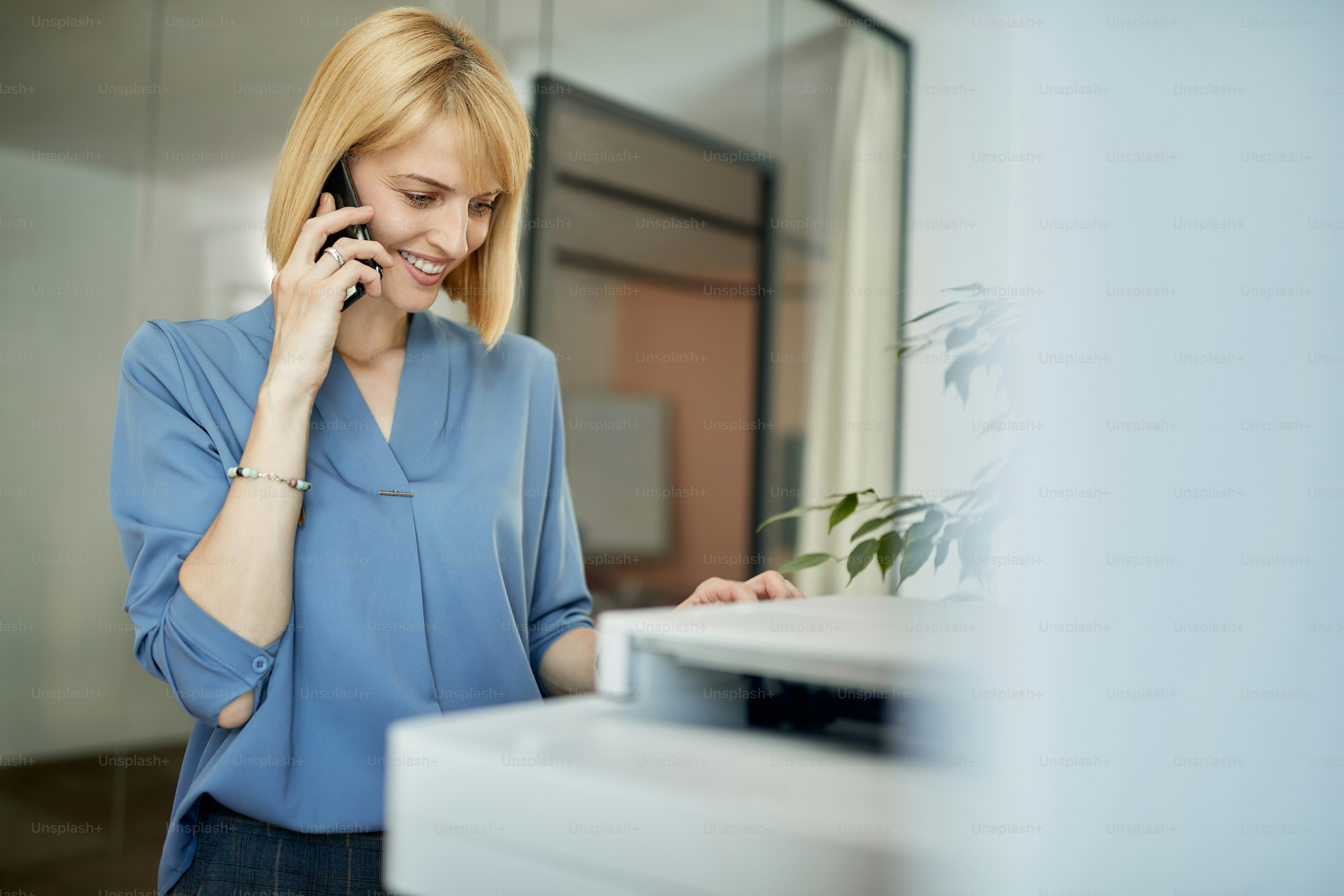 Happy businesswoman printing documents and communicating over mobile ...