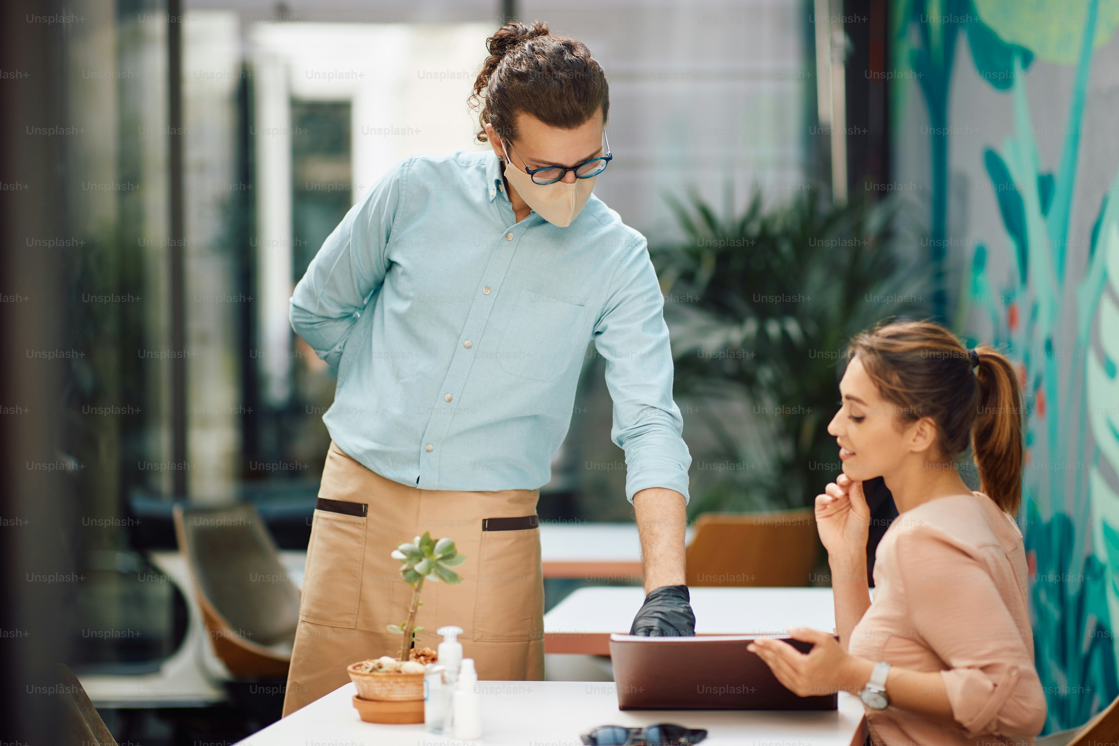 Waiter advising female guest with choosing an order from restaurant ...