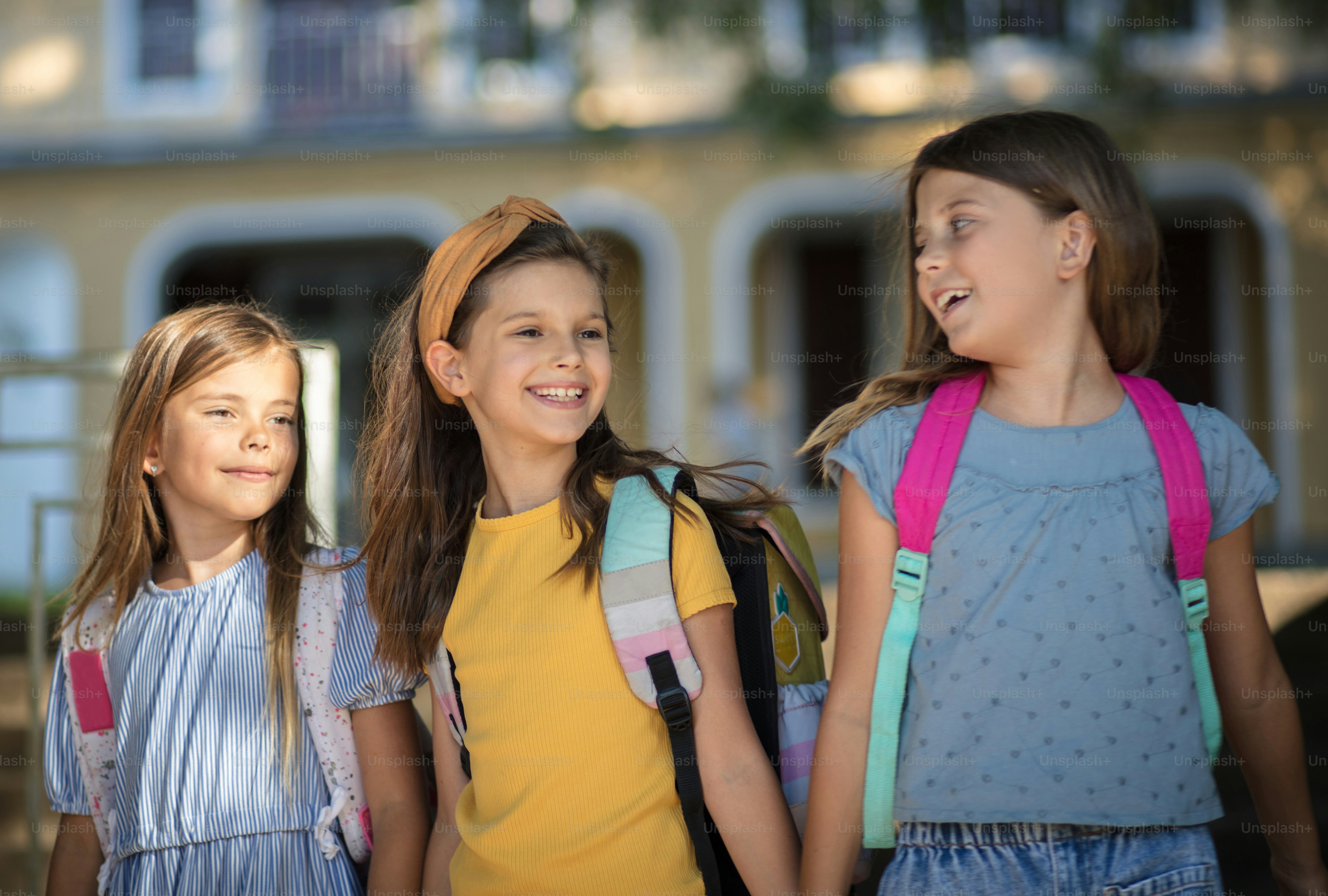 Three little smiling girls going home after school. photo – Middle ...