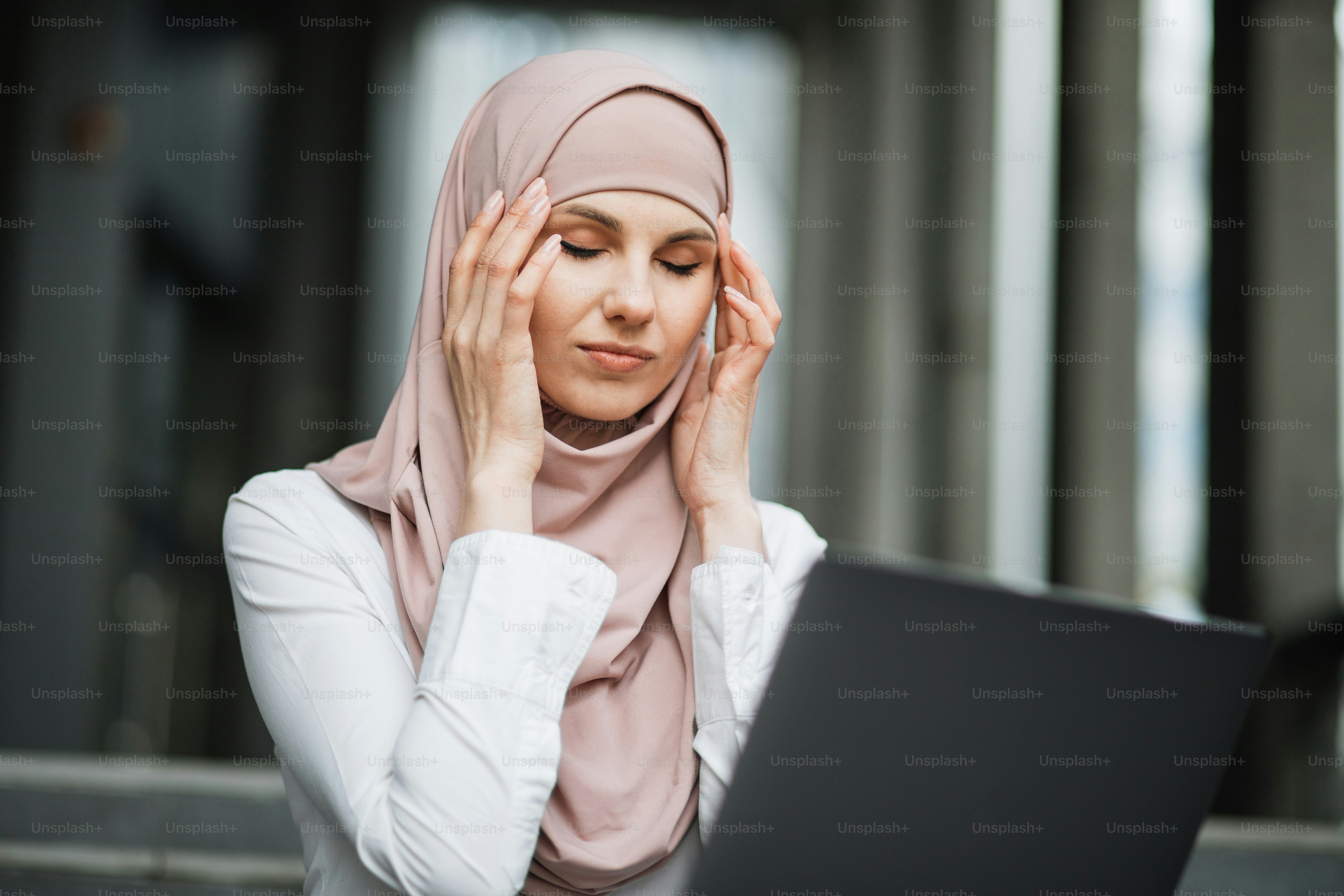 Arabian woman in hijab sitting on stairs with modern laptop on knees ...