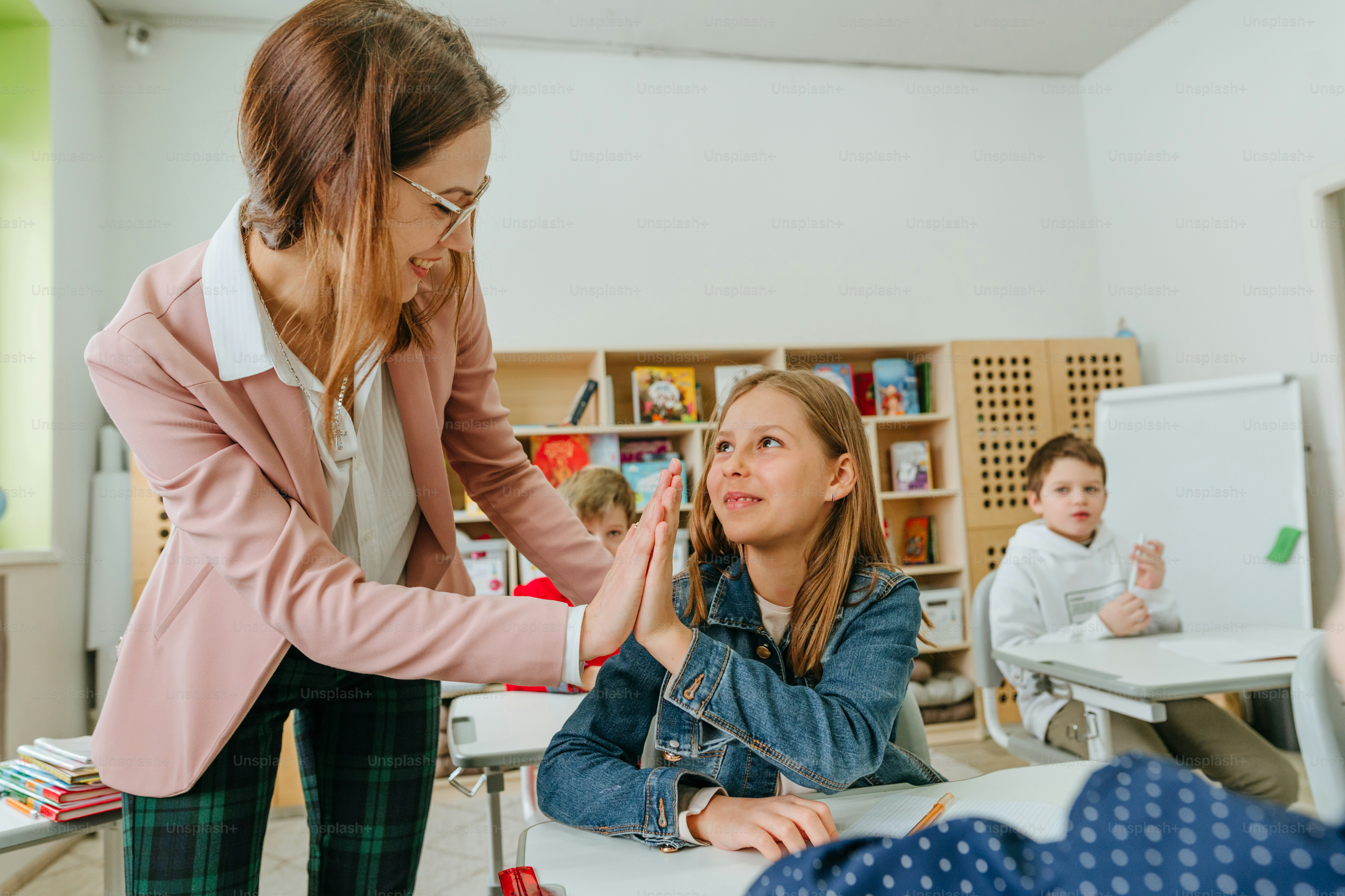Female teacher and student giving high five in the classroom at modern ...