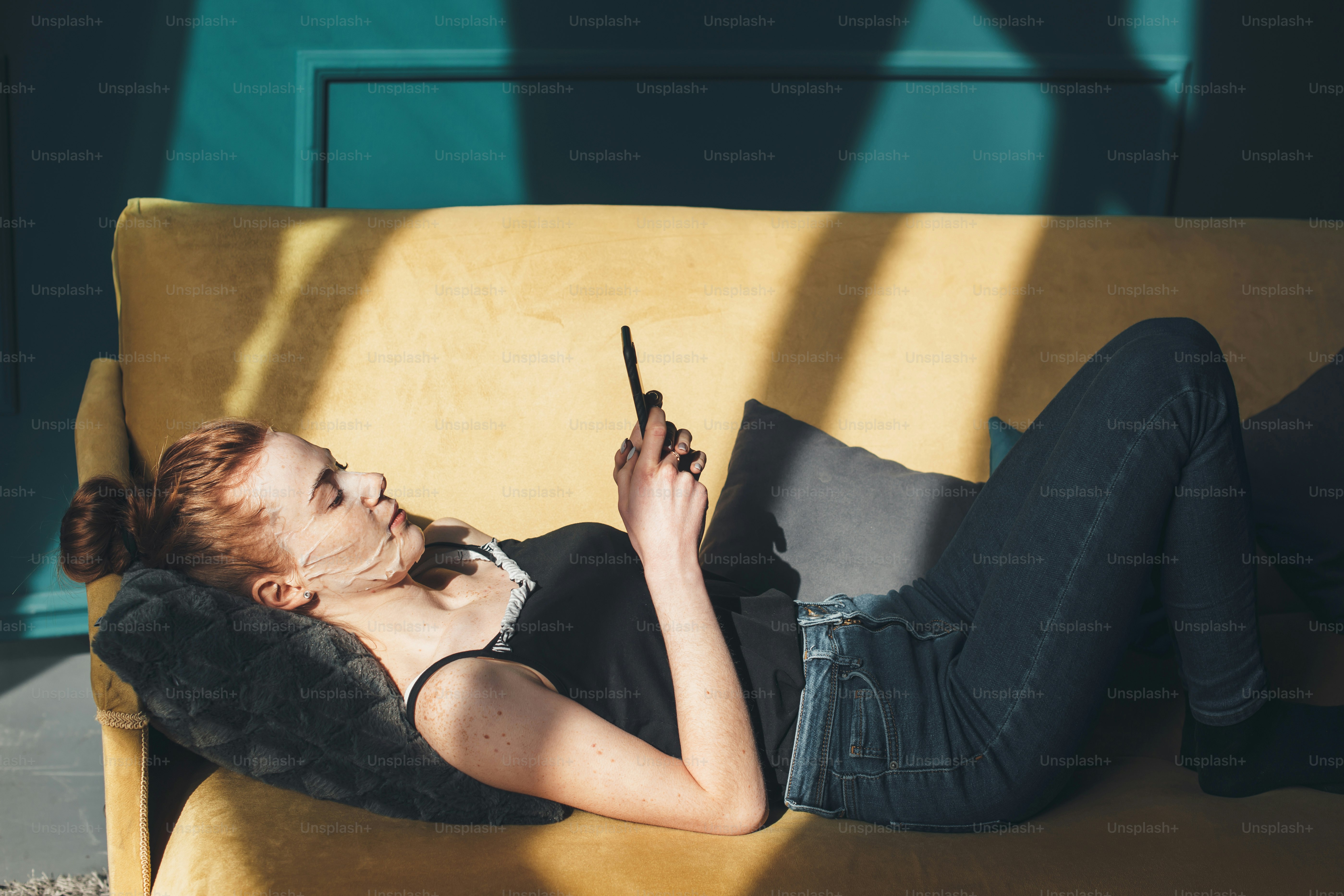 Foto La adorable mujer pelirroja está tumbada en el sofá charlando por ...