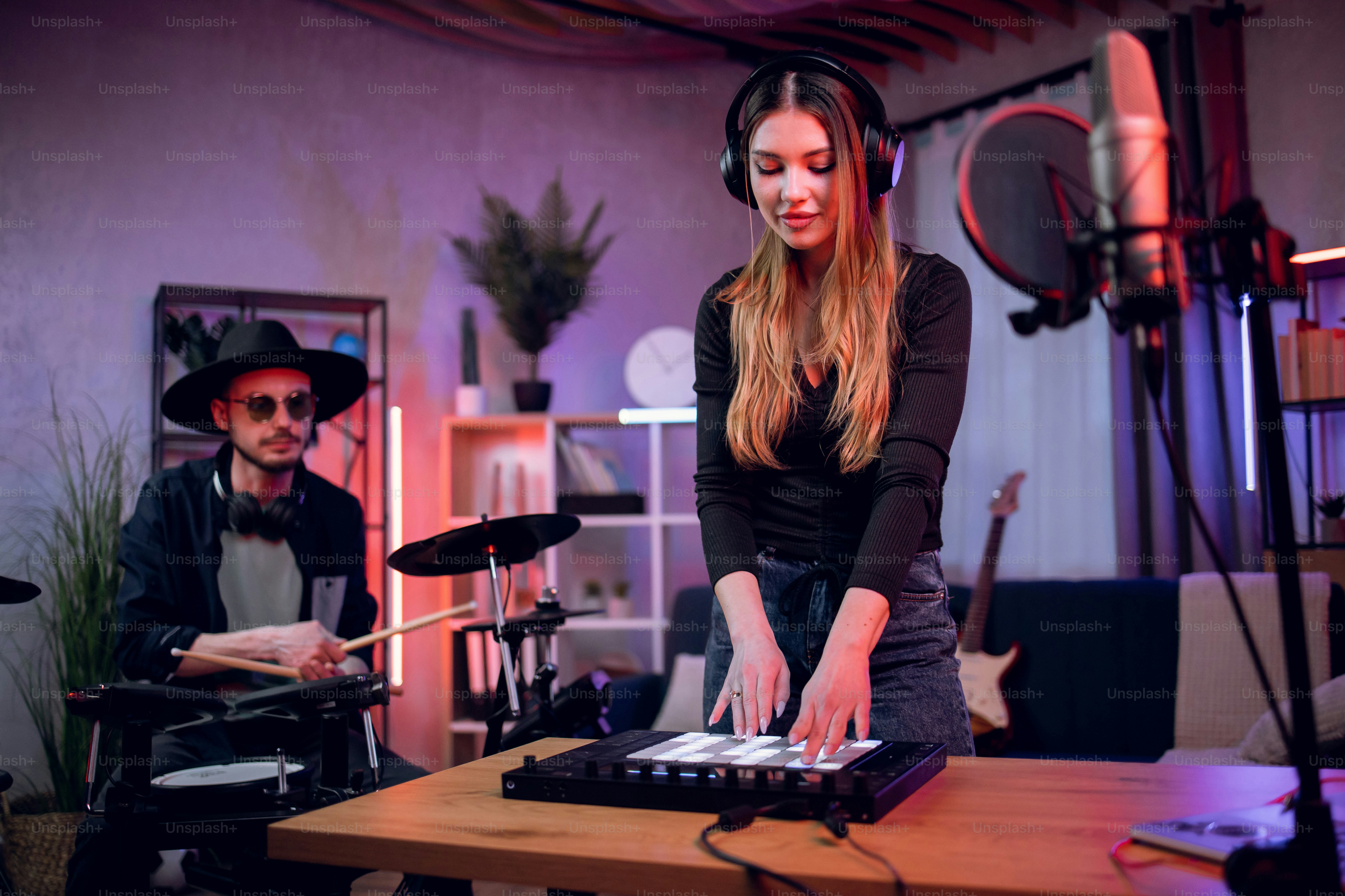 Caucasian man playing electronic drums while woman mixing sound on ...