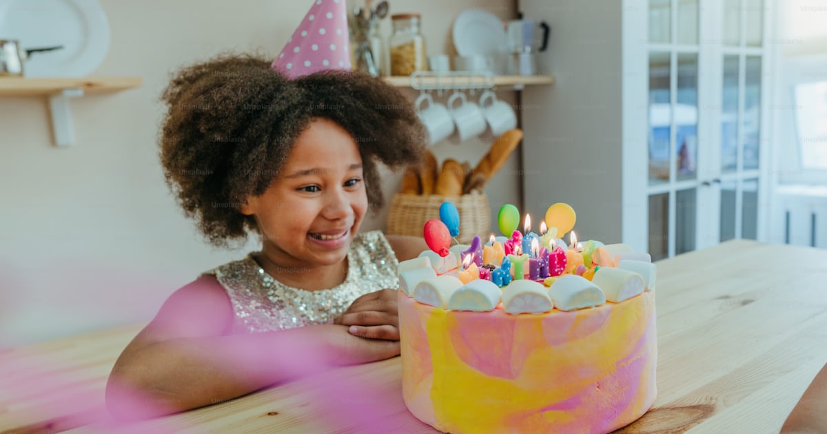 부엌에서 생일 파티를 하는 동안 촛불로 생일 케이크를 보고 있는 행복한 소녀 소녀의 얼굴에 선택적 초점 사진