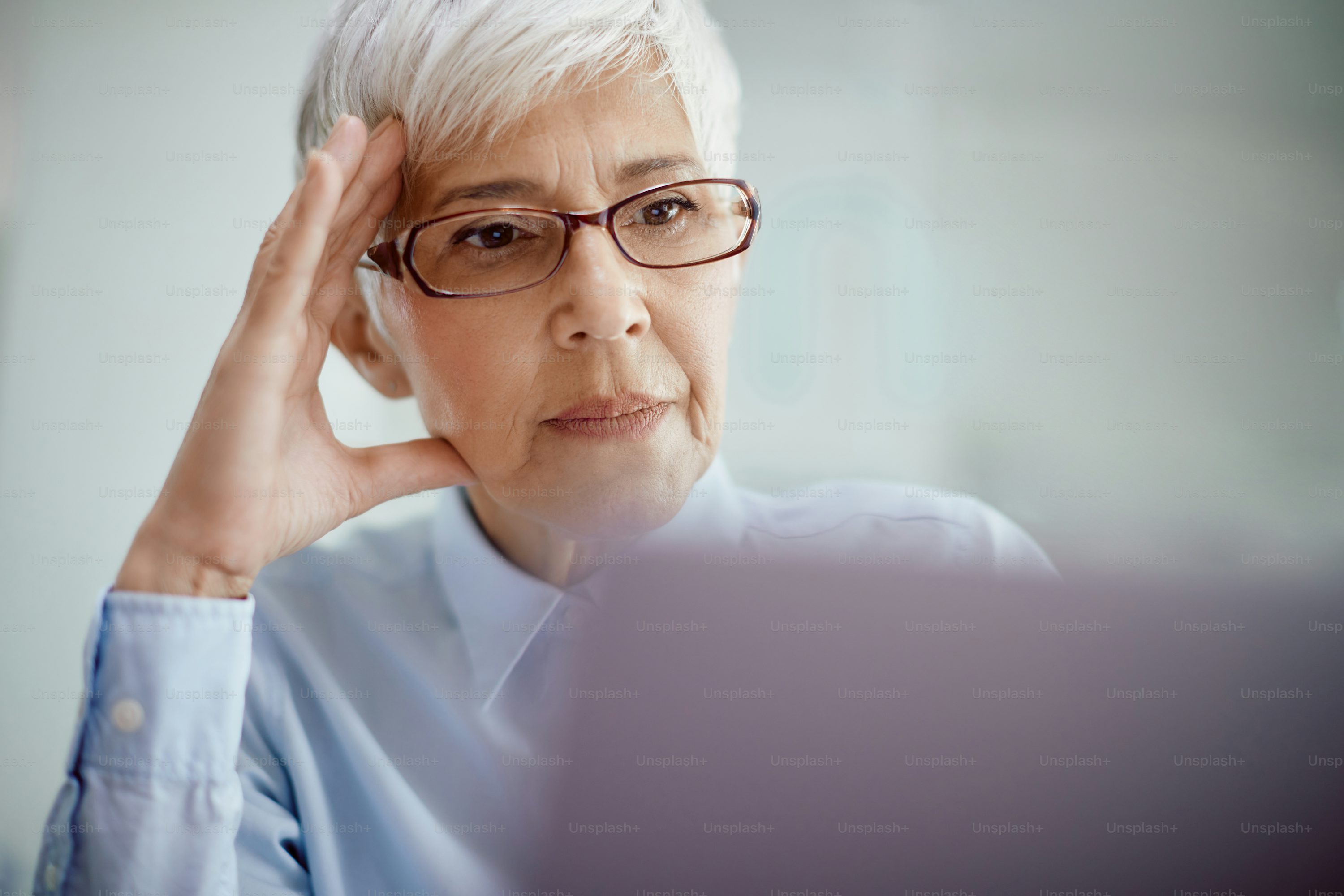 Thoughtful senior businesswoman reading problematic e-mail while ... Thoughtful senior businesswoman reading problematic e-mail while ...