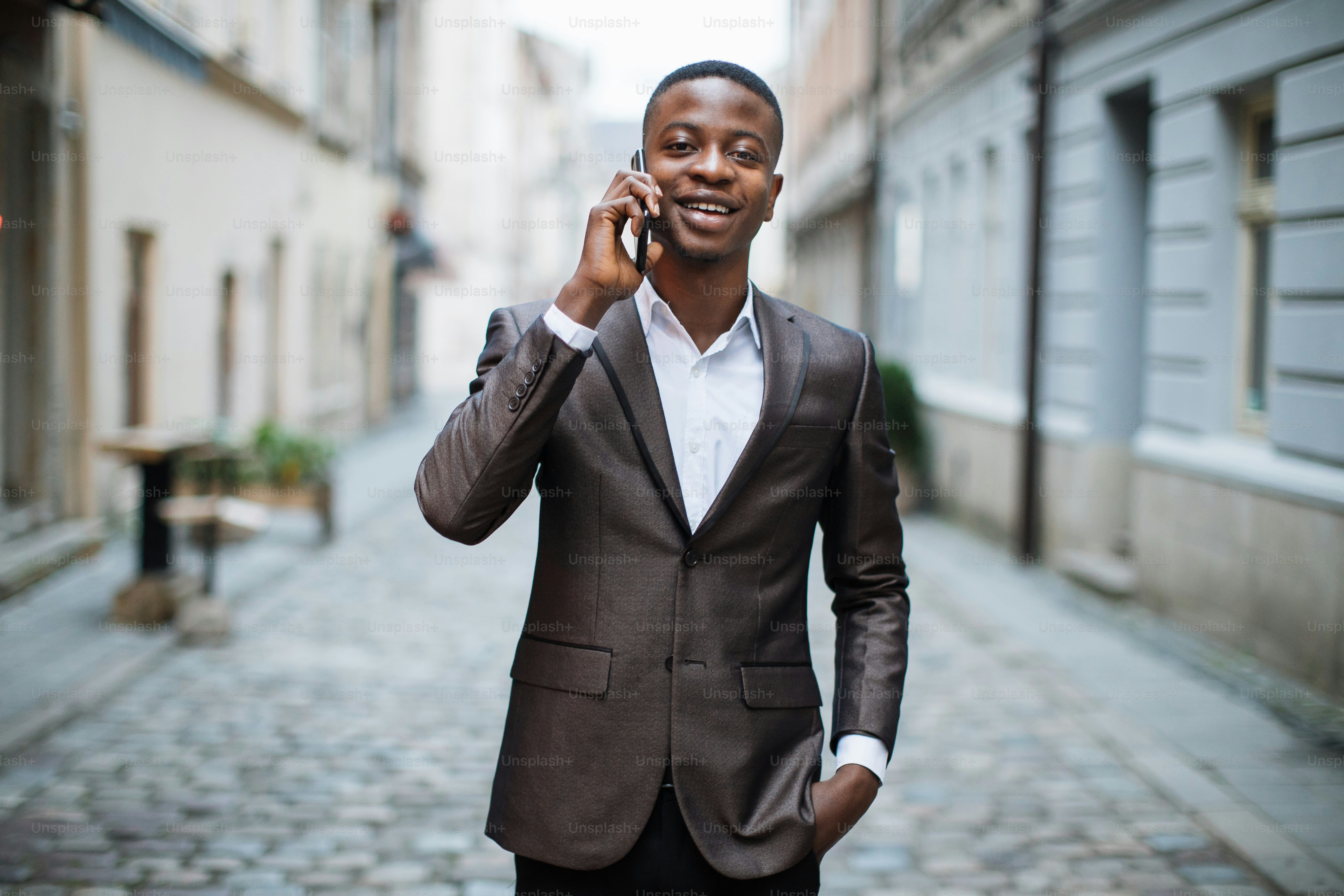 African man in business suit having mobile conversation while walking ...