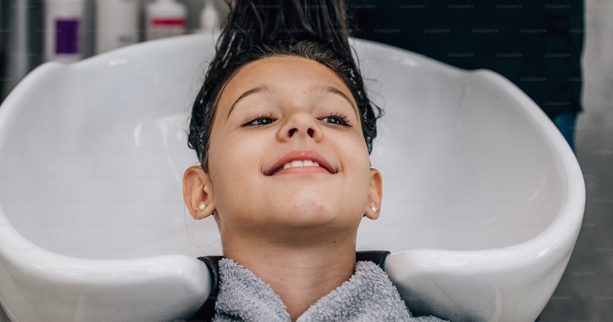 Young Girl At Hairstyle Treatment While Professional Hairdresser Gently