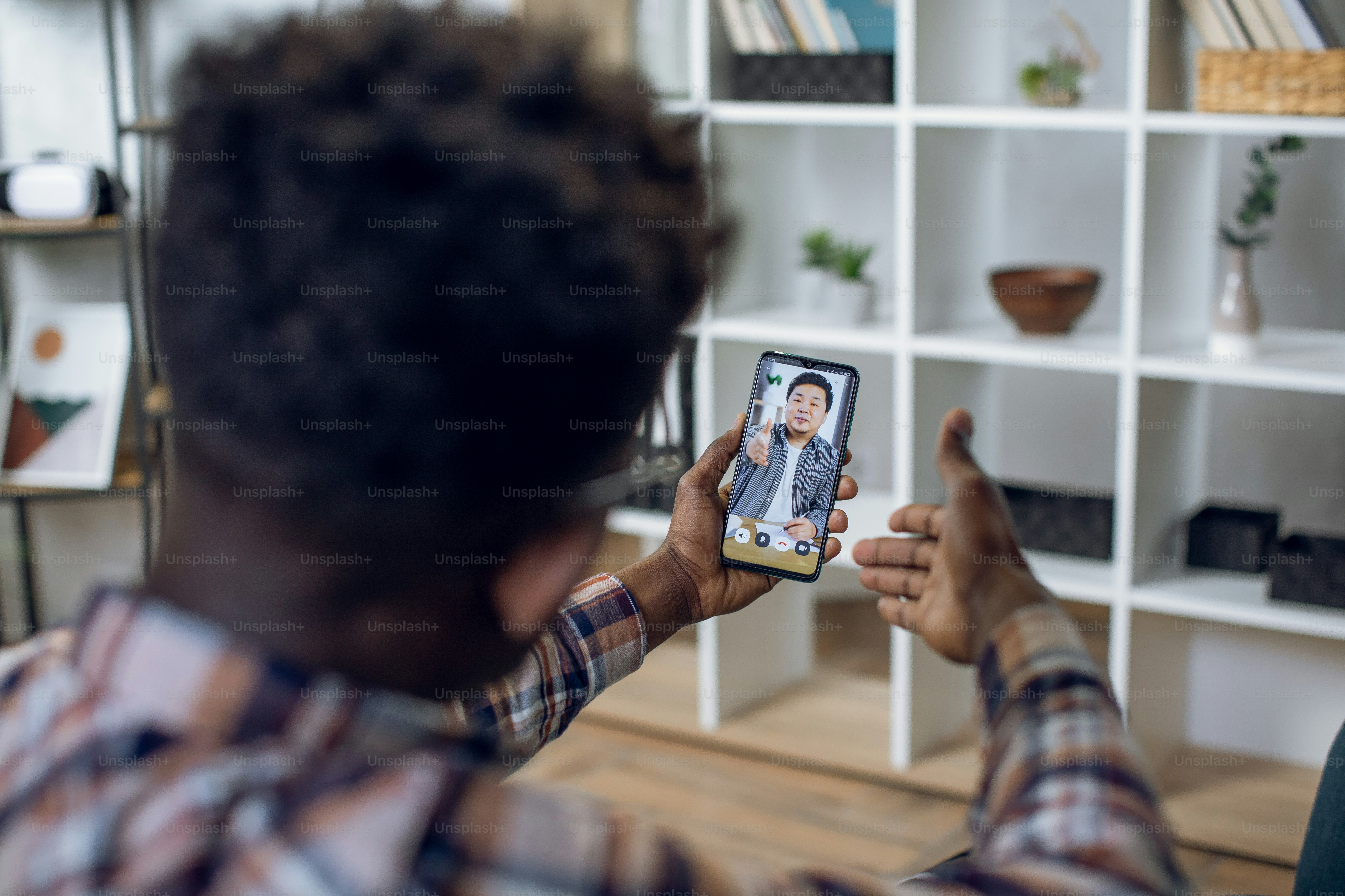 Young black man sitting at home and using modern smartphone for online ...