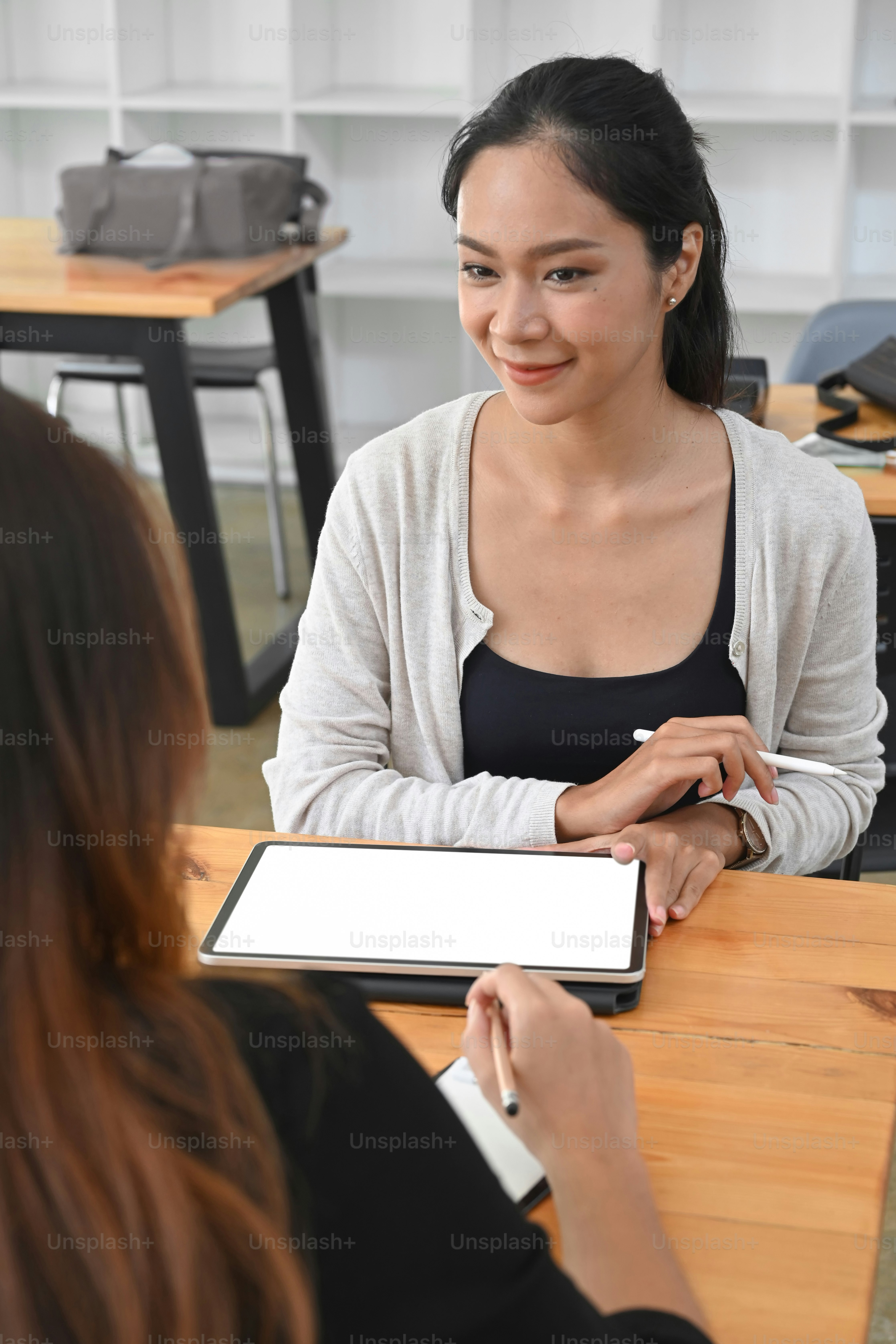 Two female colleagues using digital tablet and discussing business plan ...